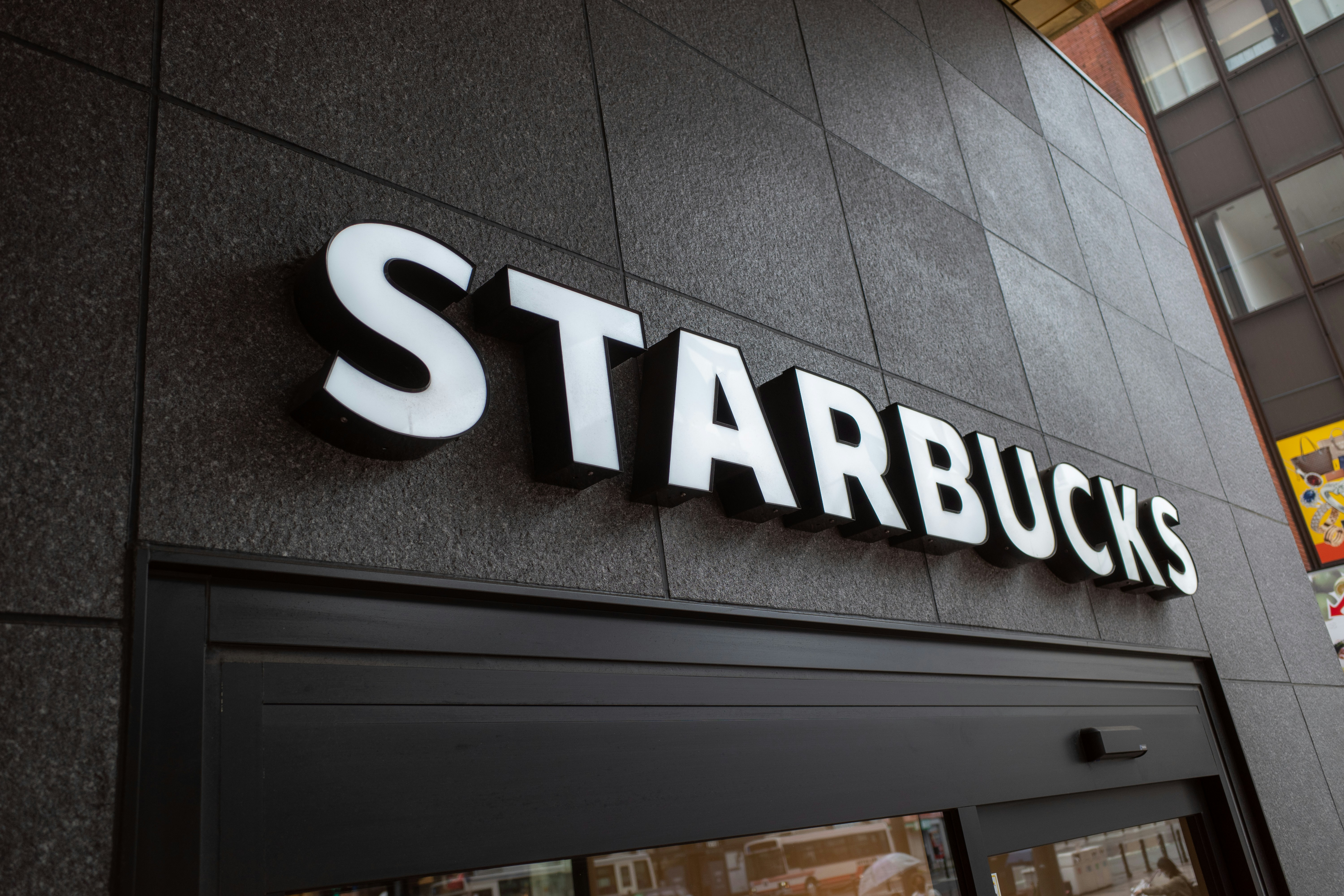 A starbucks sign on the side of a building photo – Free Grey Image on ...