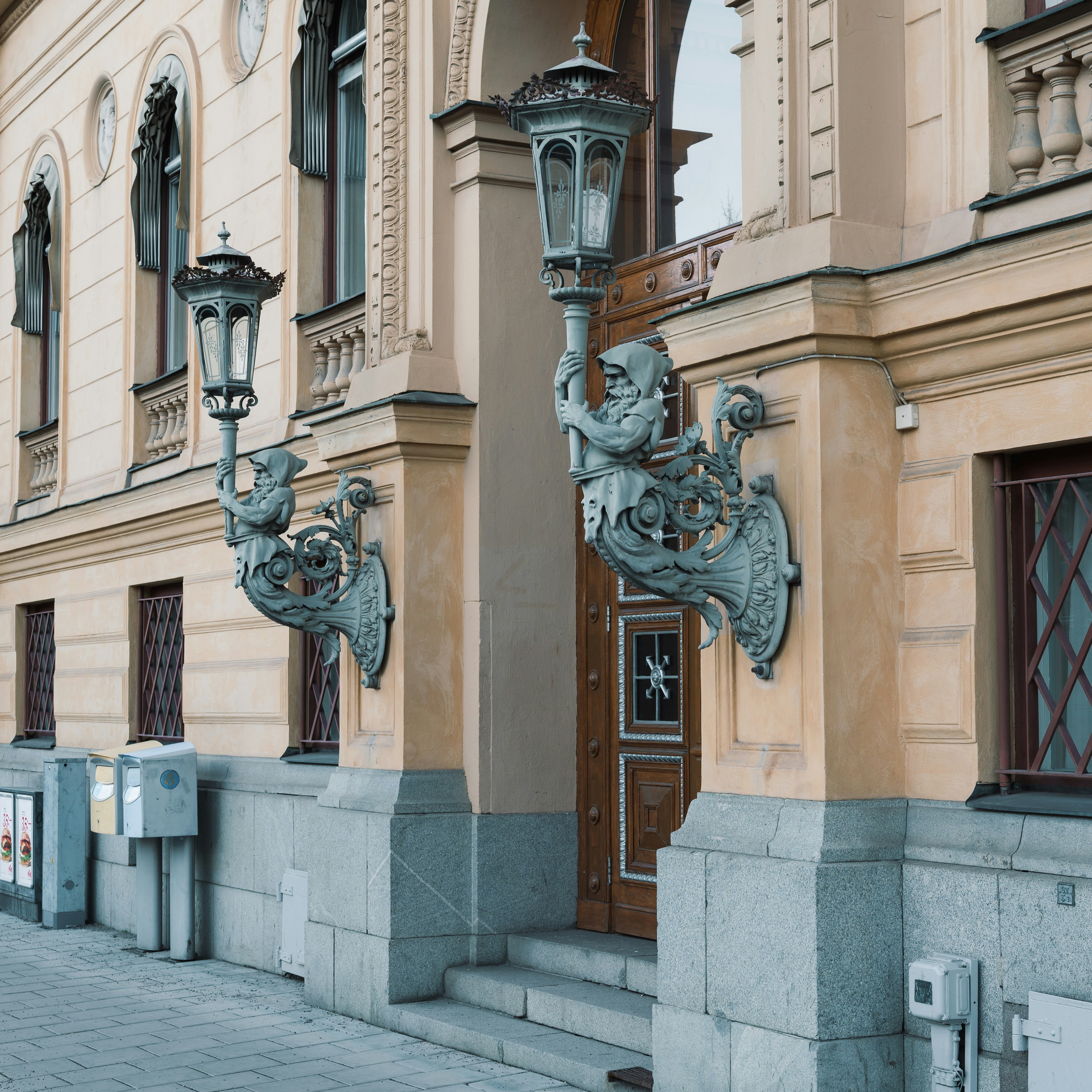 Intricate facade of a historic building featuring ornate lanterns and decorative elements. The craftsmanship highlights the architectural beauty of the structure.