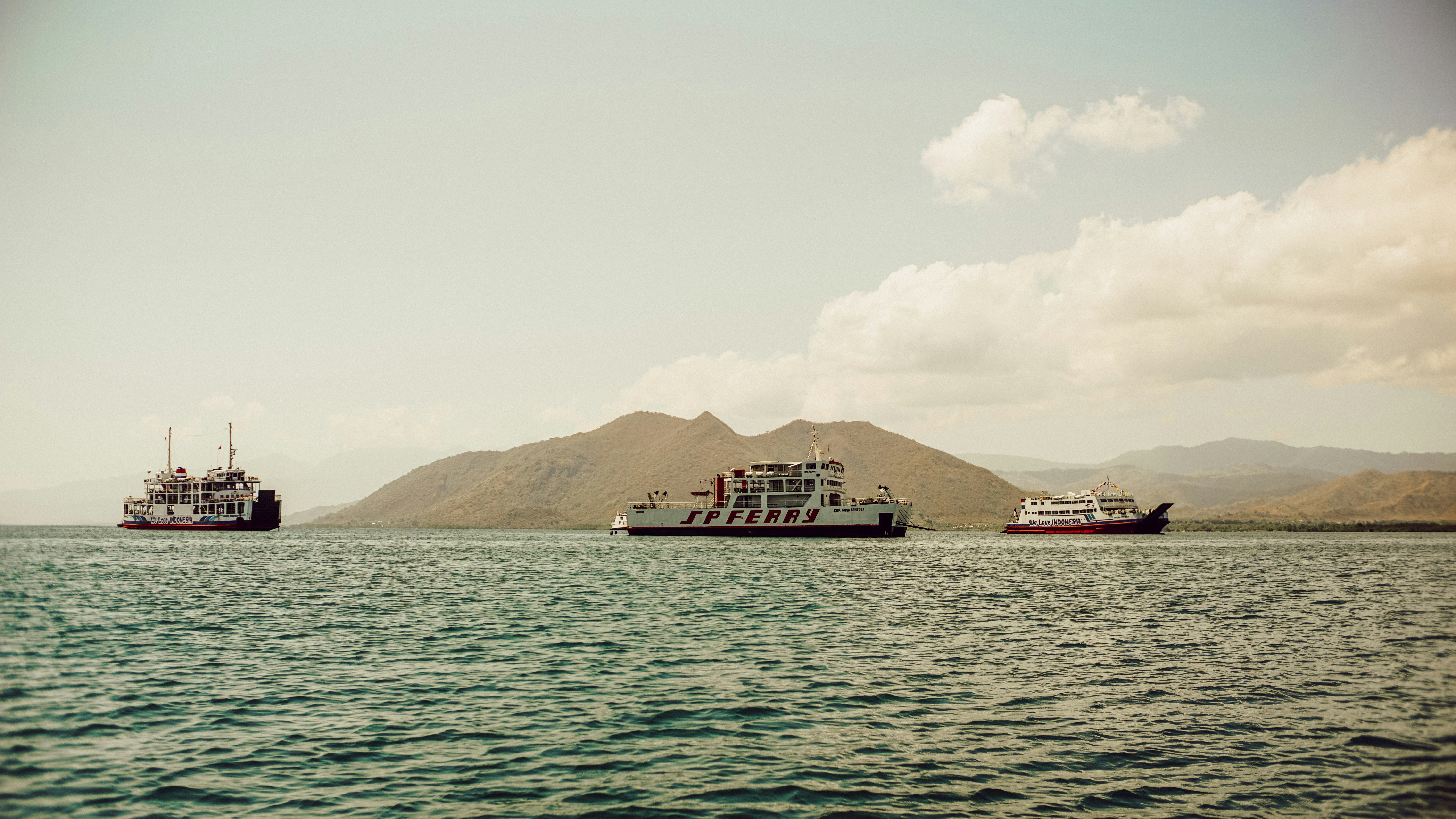 Three Ships Across a Quiet Sea Before a Distant Arid Island Horizon