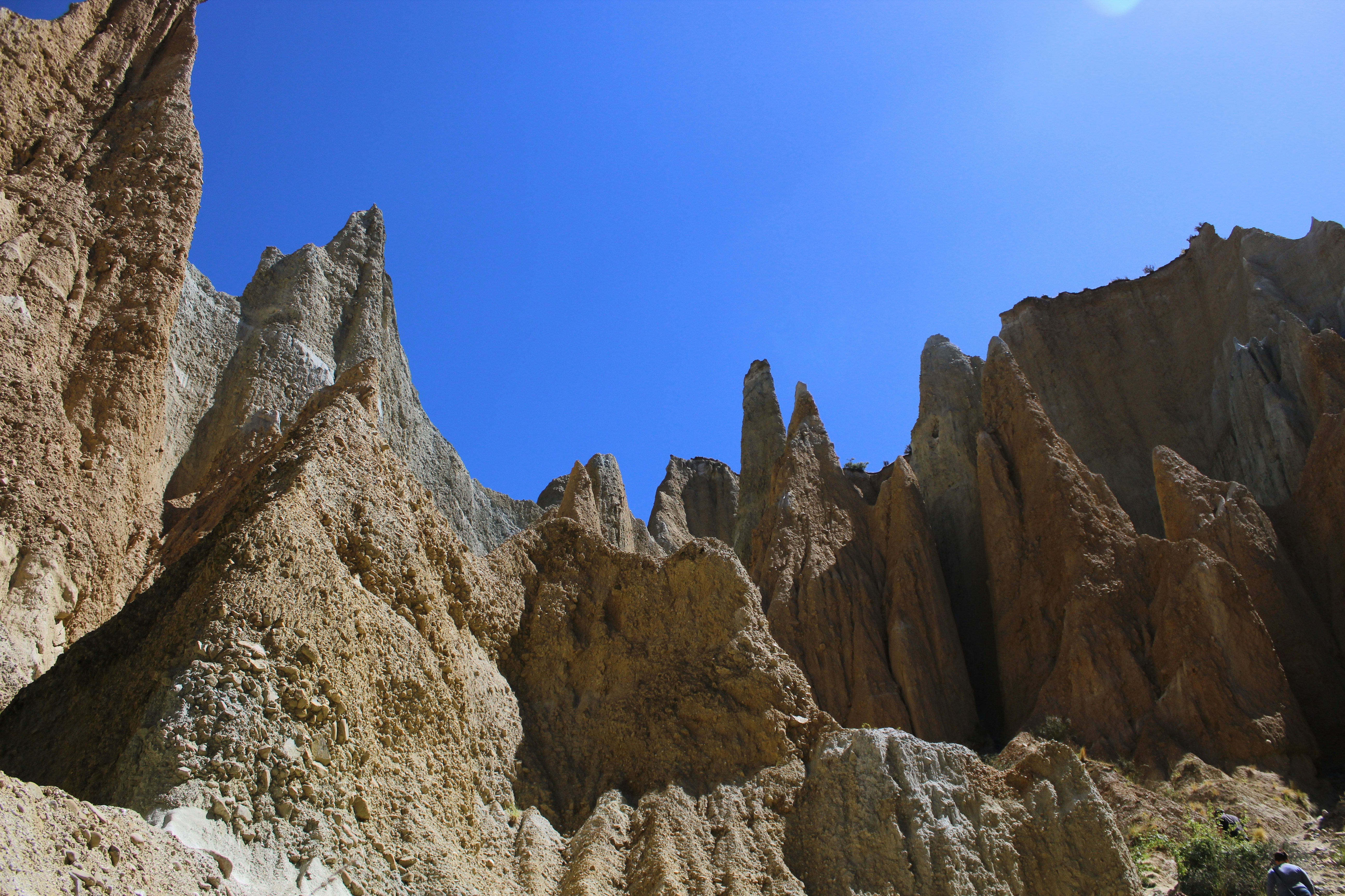 Dramatic rock formations rise against a clear blue sky, showcasing the intricate textures and colors of the earth's surface.