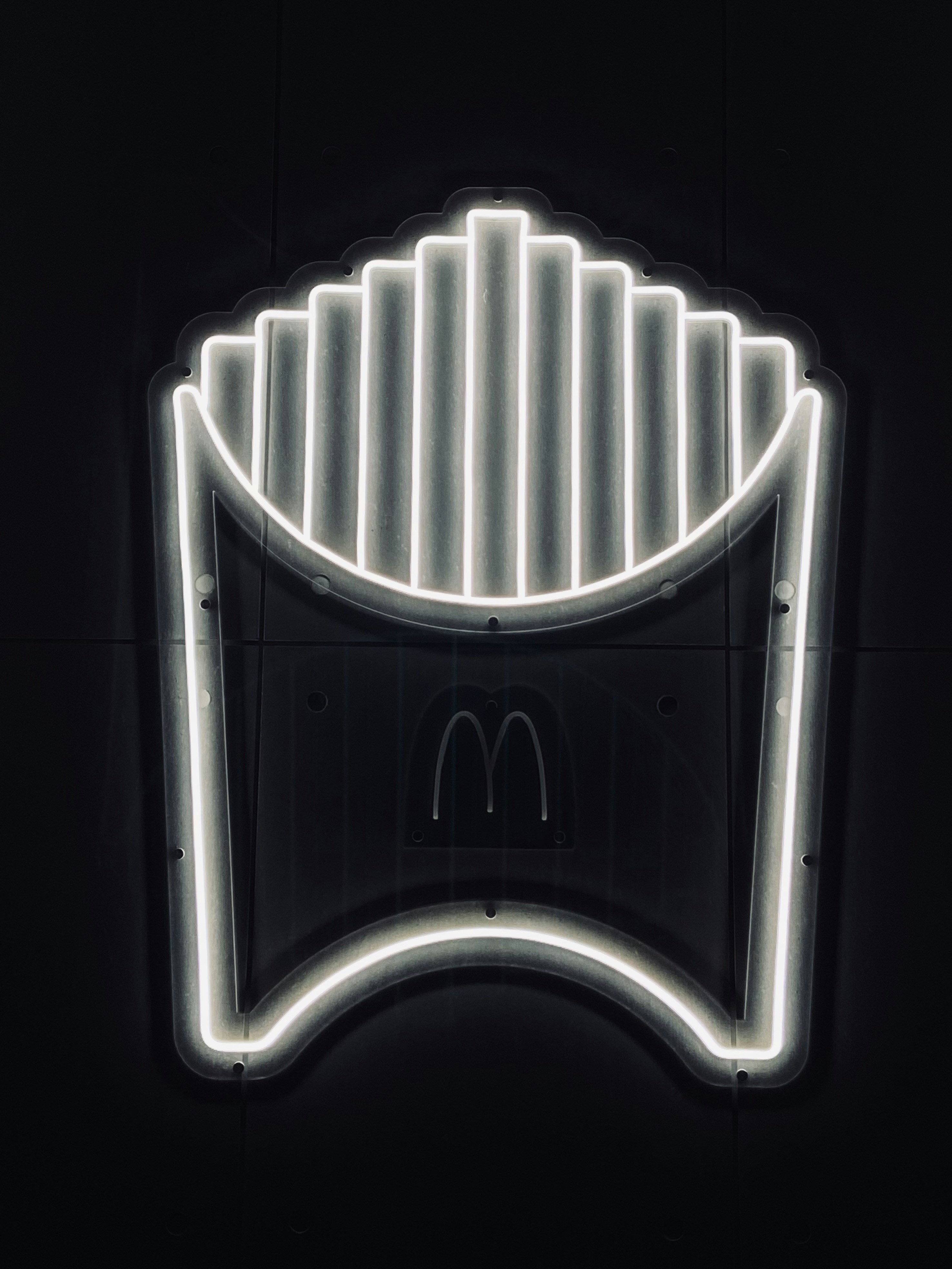 Neon Crown of Fries: A McDonald's Sign Illuminates a Dark Wall