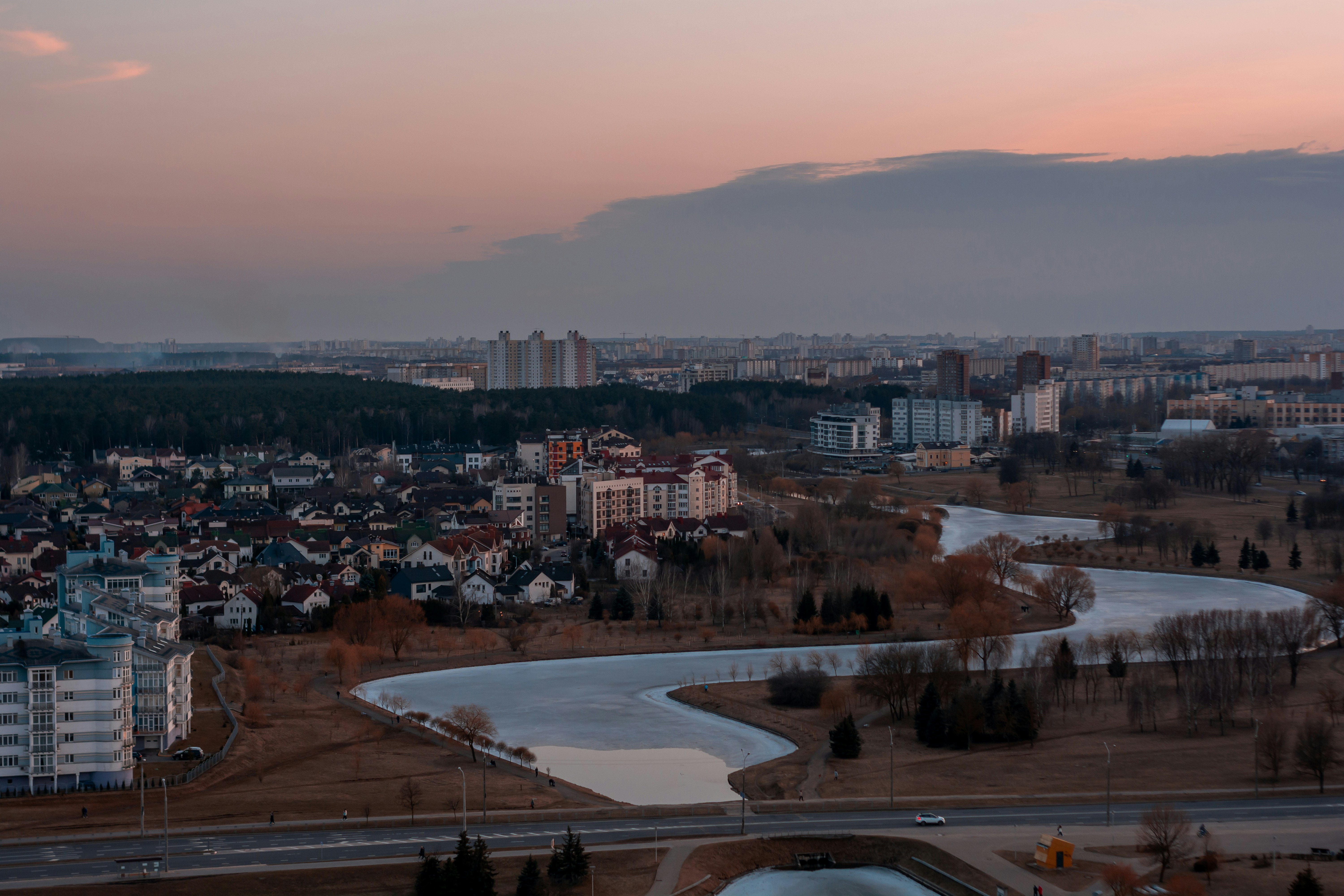 Aerial view of a cityscape at dusk with a winding river reflecting the fading light.