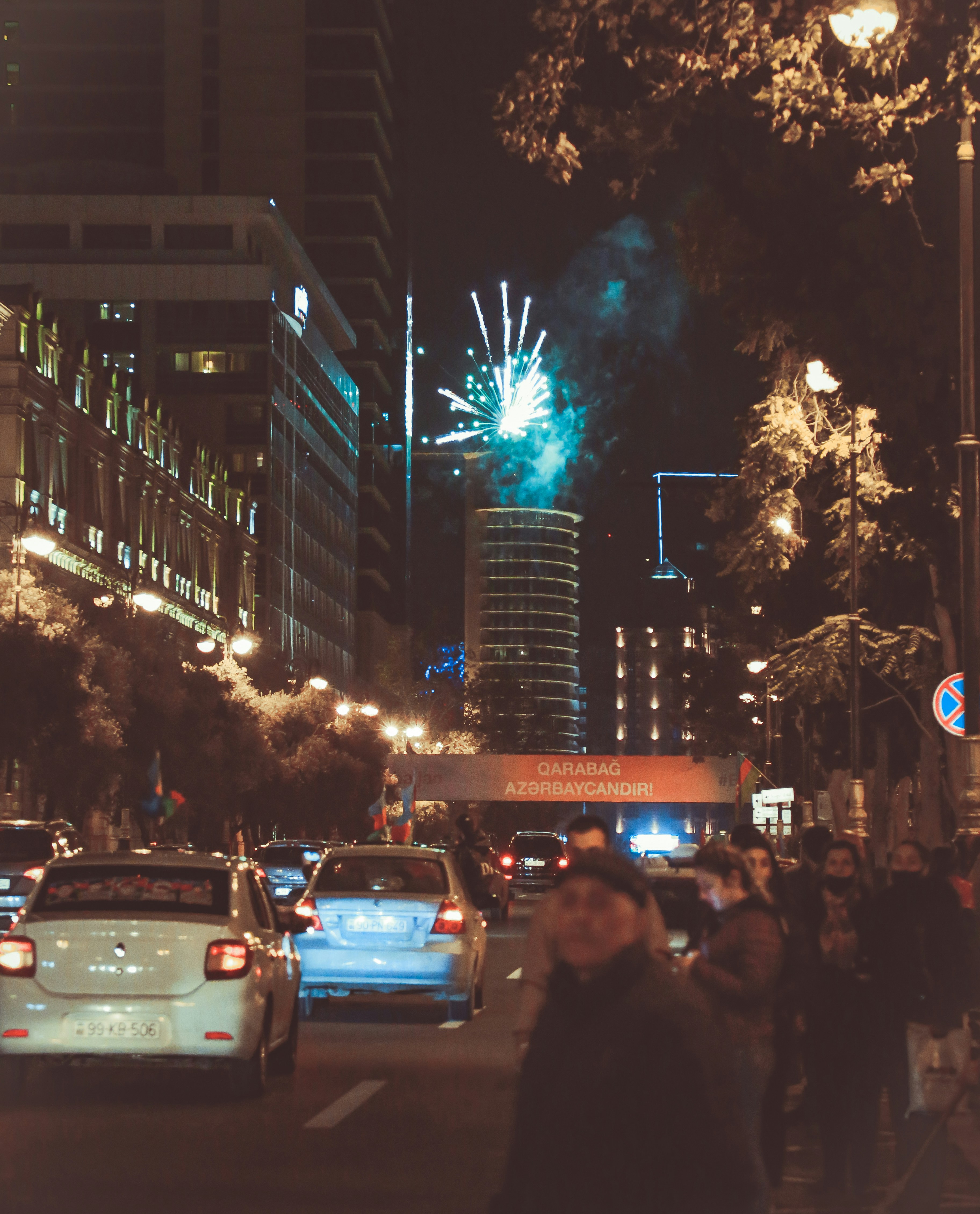 Fireworks Over a Blue-Tinted Tower: Nightlife on a Bustling City Street