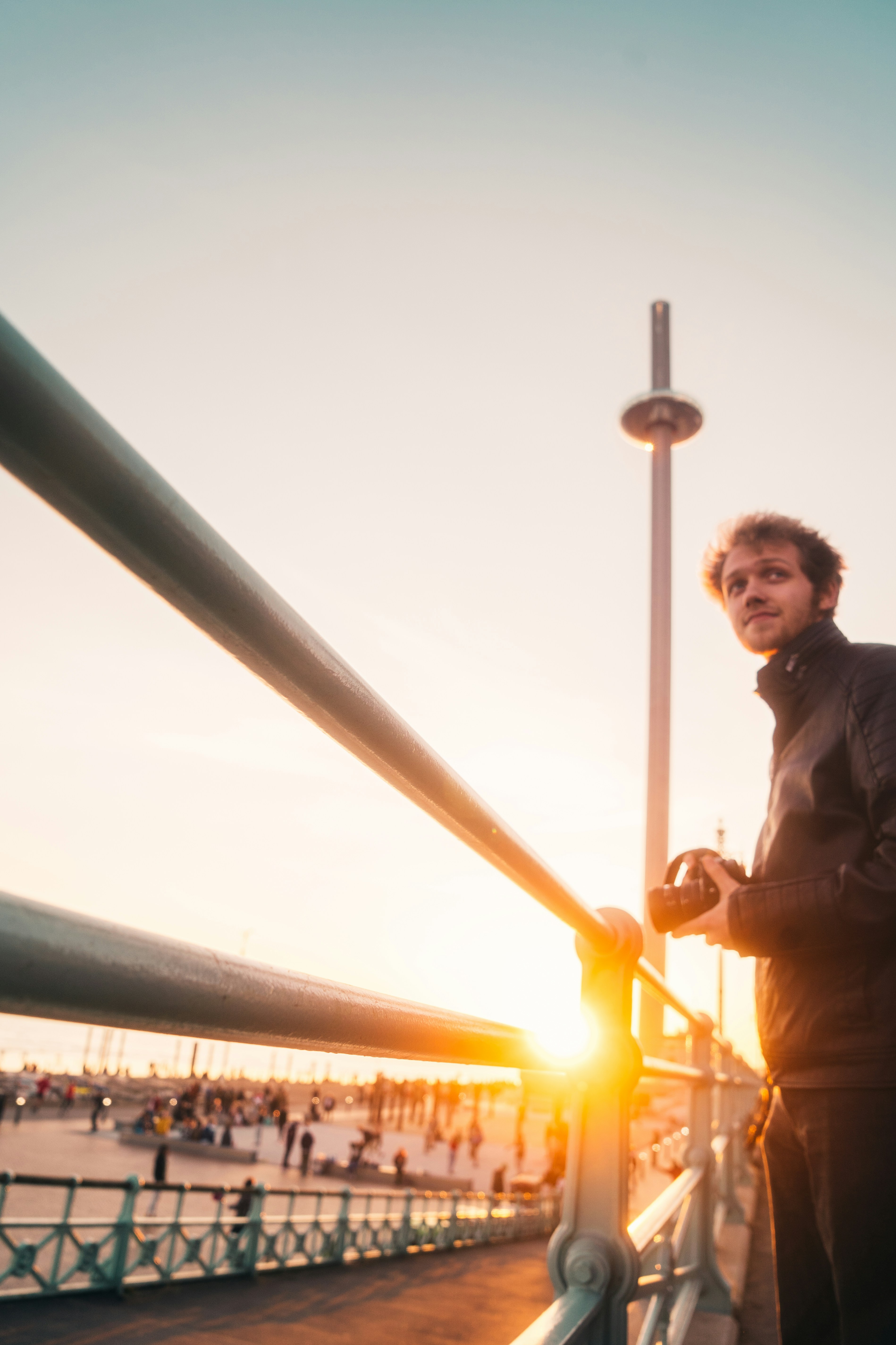 Man in black jacket standing beside yellow metal post during daytime ...