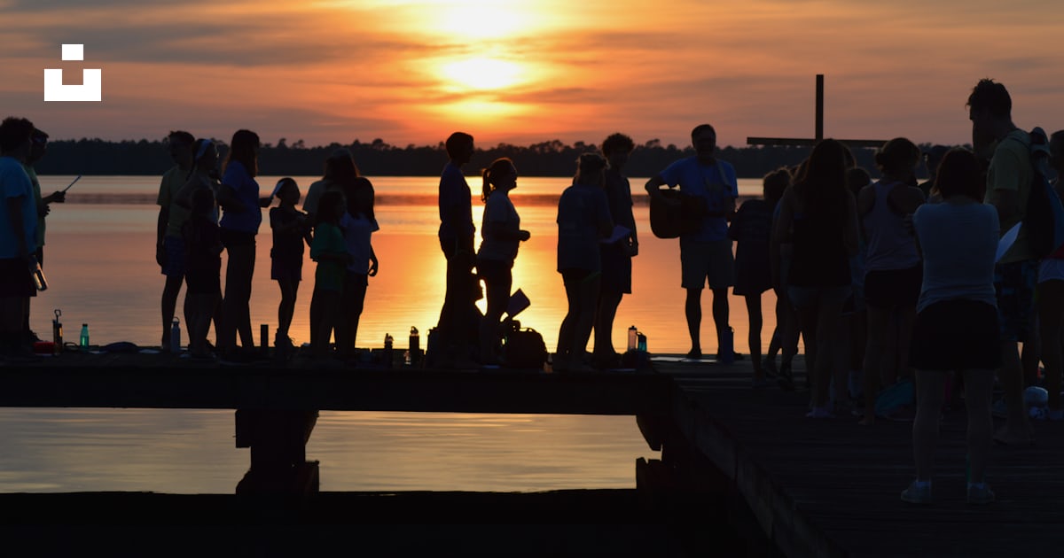 Silueta De Personas De Pie En El Muelle Durante La Puesta Del Sol Foto