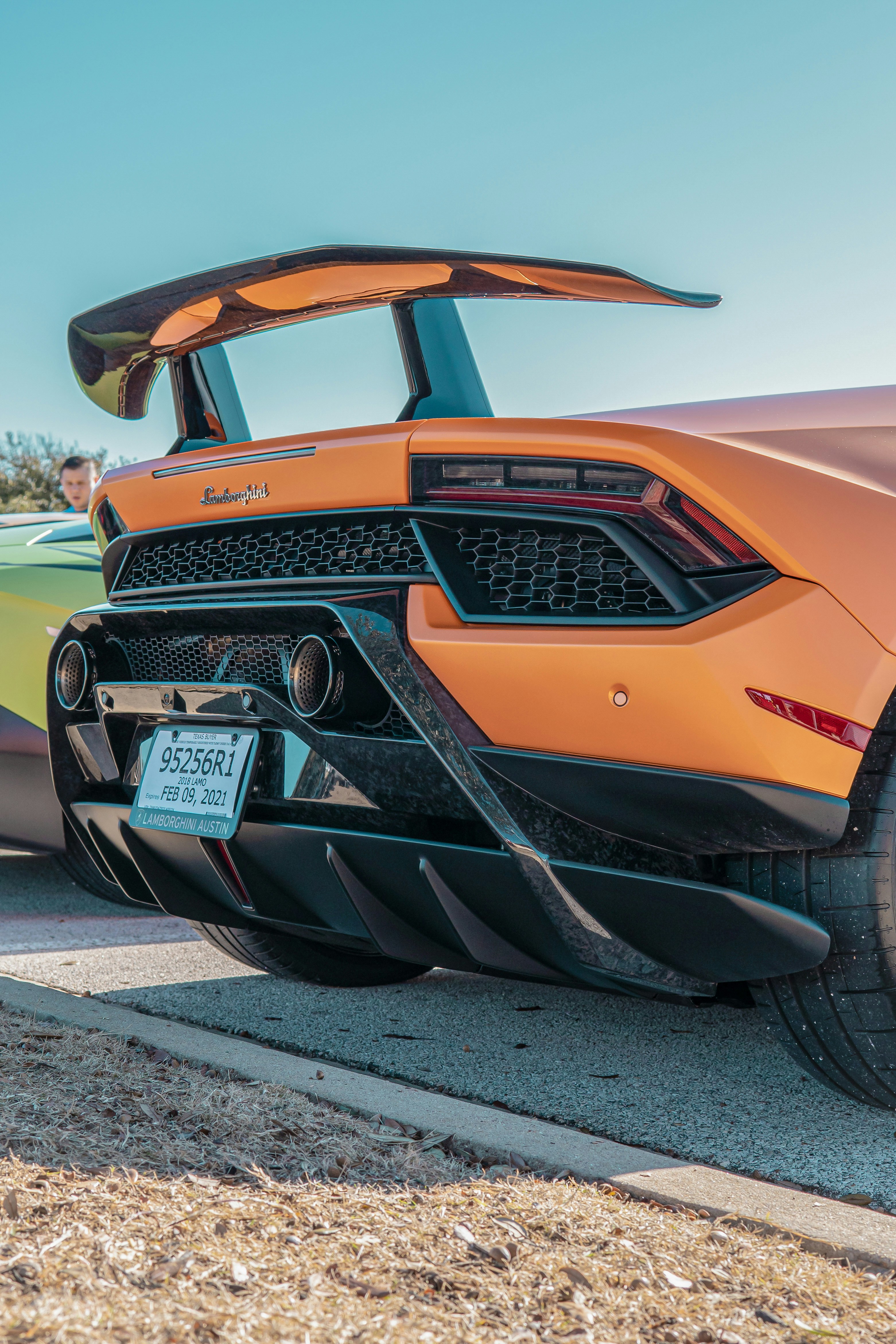 Rear view of a vibrant orange Lamborghini showcasing its aerodynamic features and sleek lines.