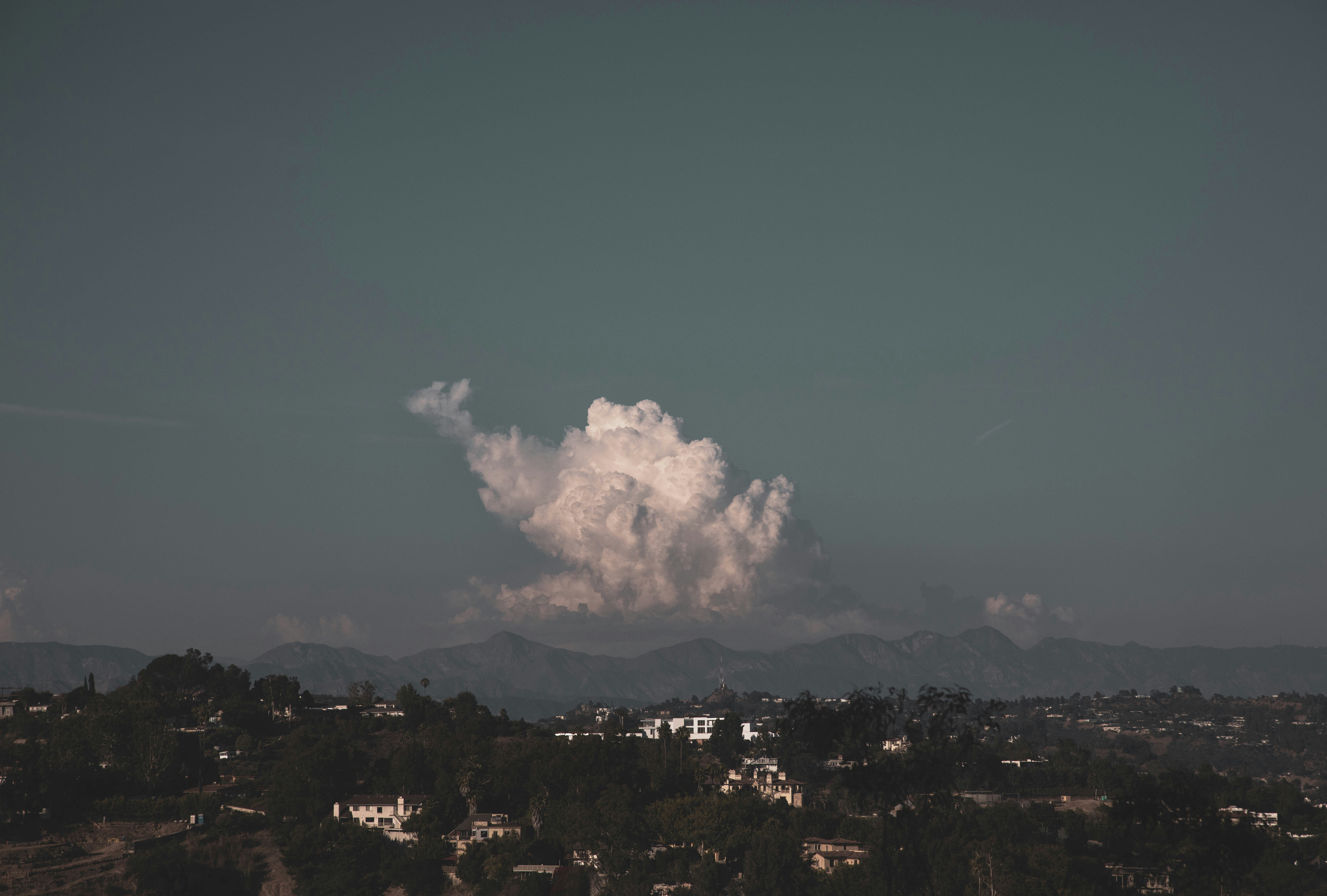 Fluffy white clouds billowing above a serene landscape, with distant mountains providing a tranquil backdrop.