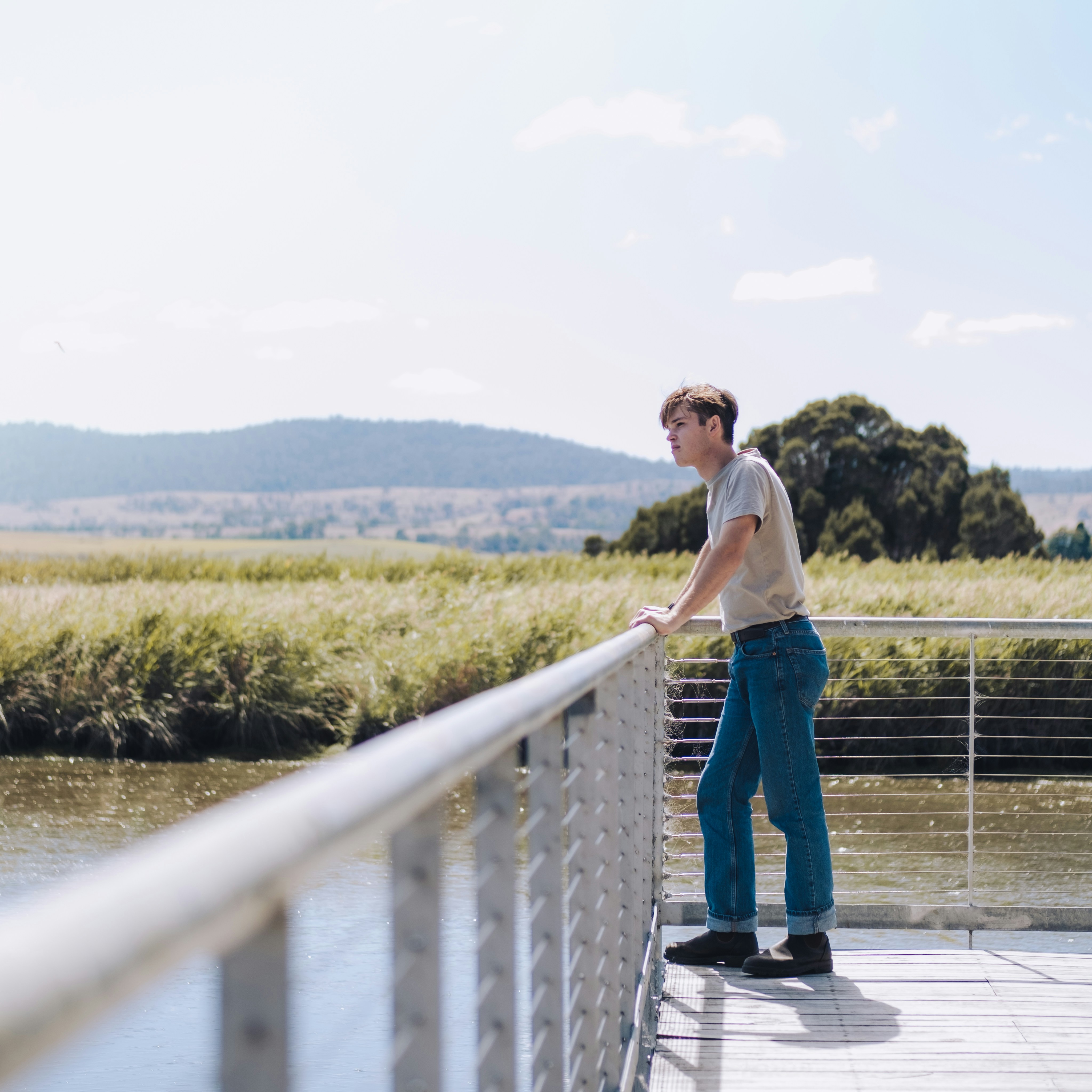 Standing on the railing: a quiet portrait on a sunlit boardwalk