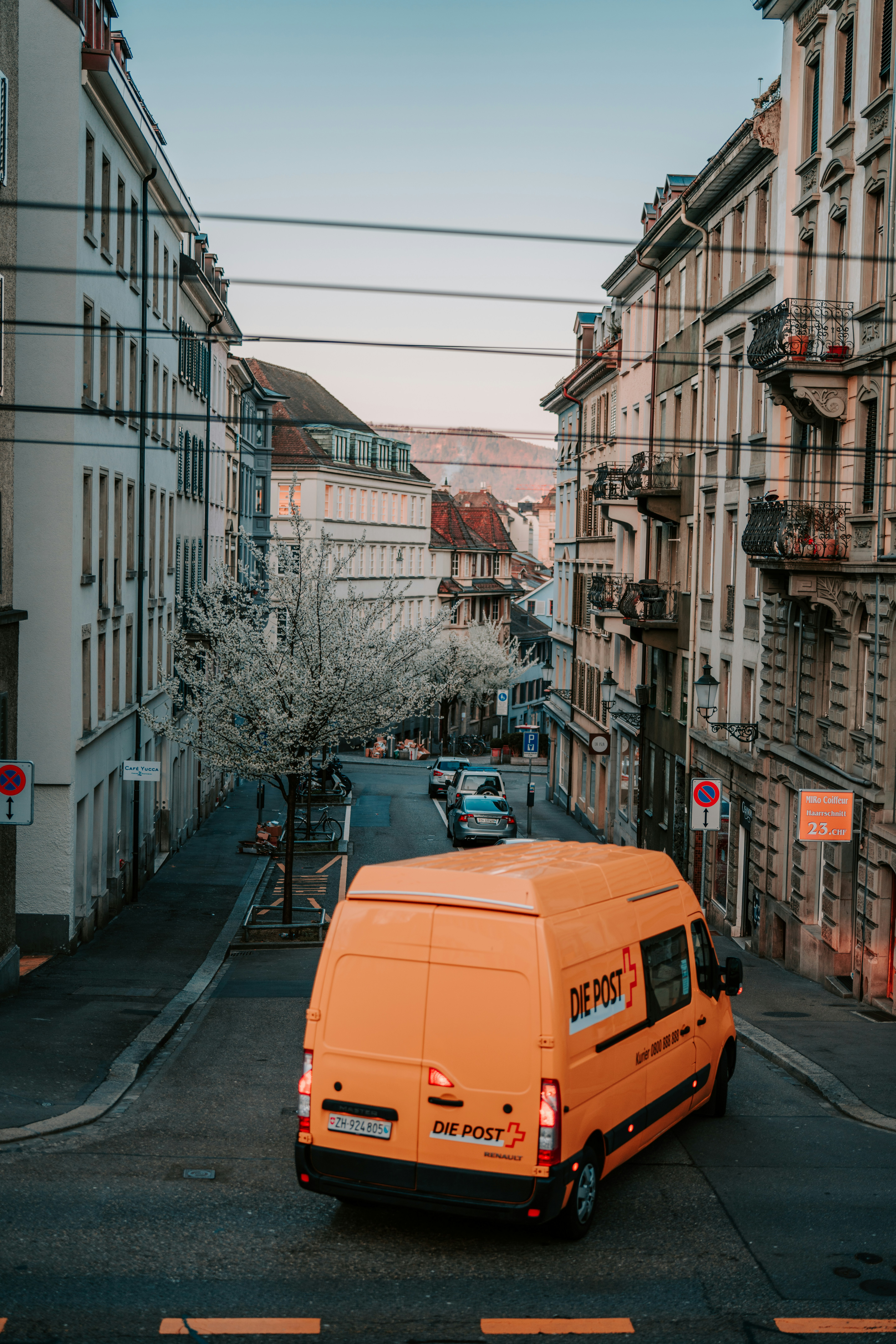 Orange Delivery Van Rounding a European Cobblestone Street