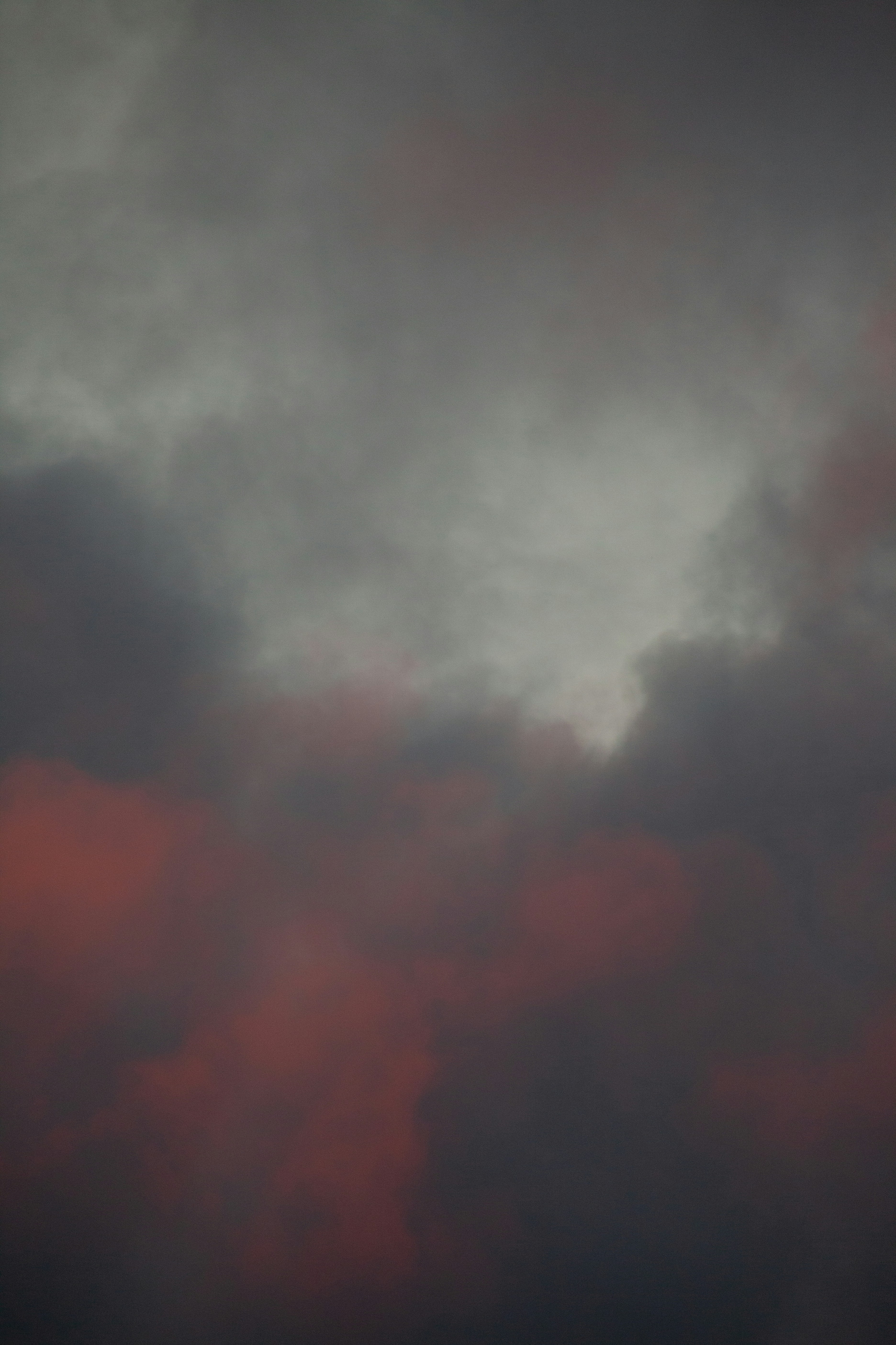 Dark storm clouds illuminated by hints of red and gray, creating a dramatic sky at twilight.