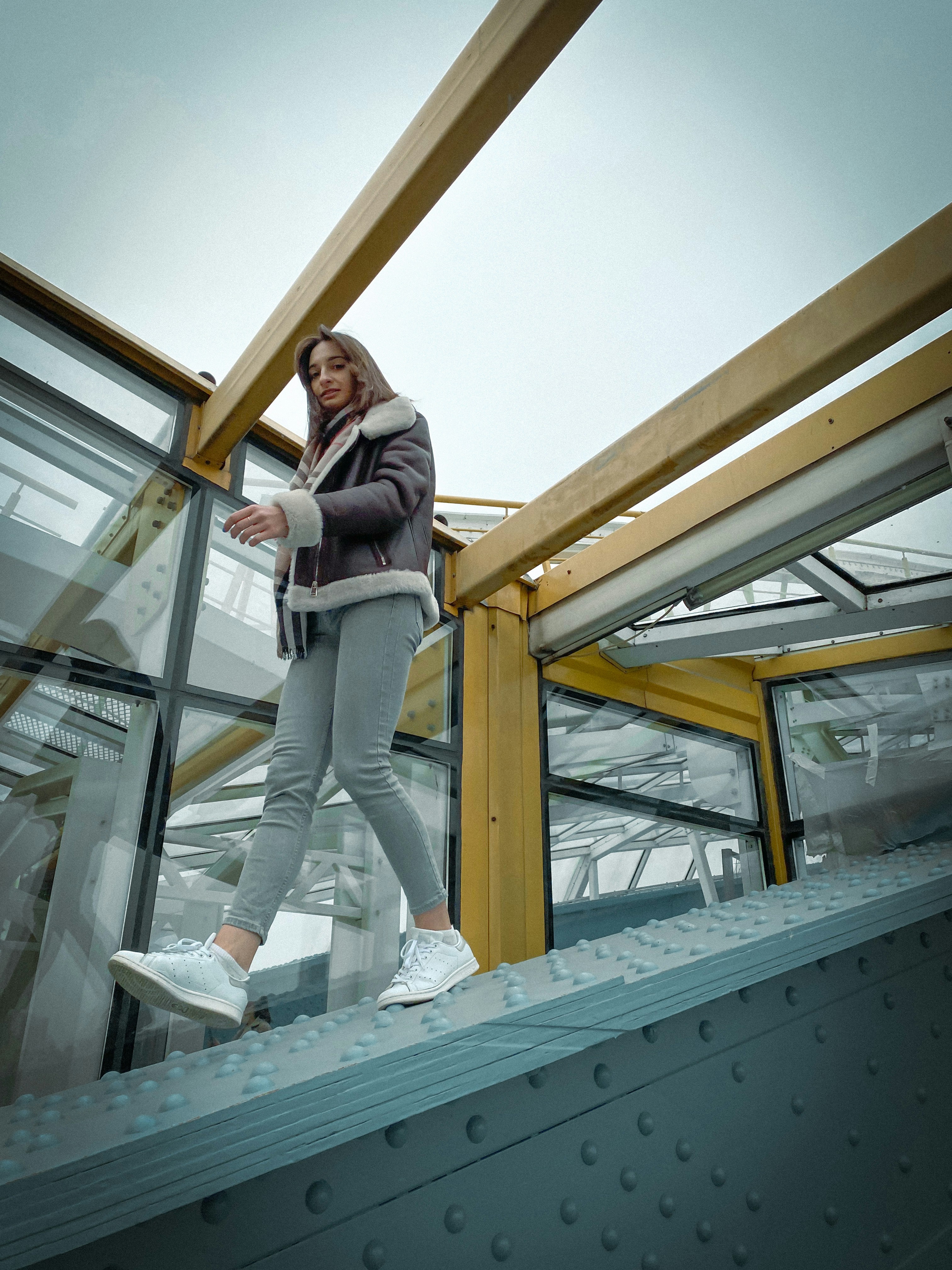 Woman in black jacket and gray pants standing on yellow metal ladder ...