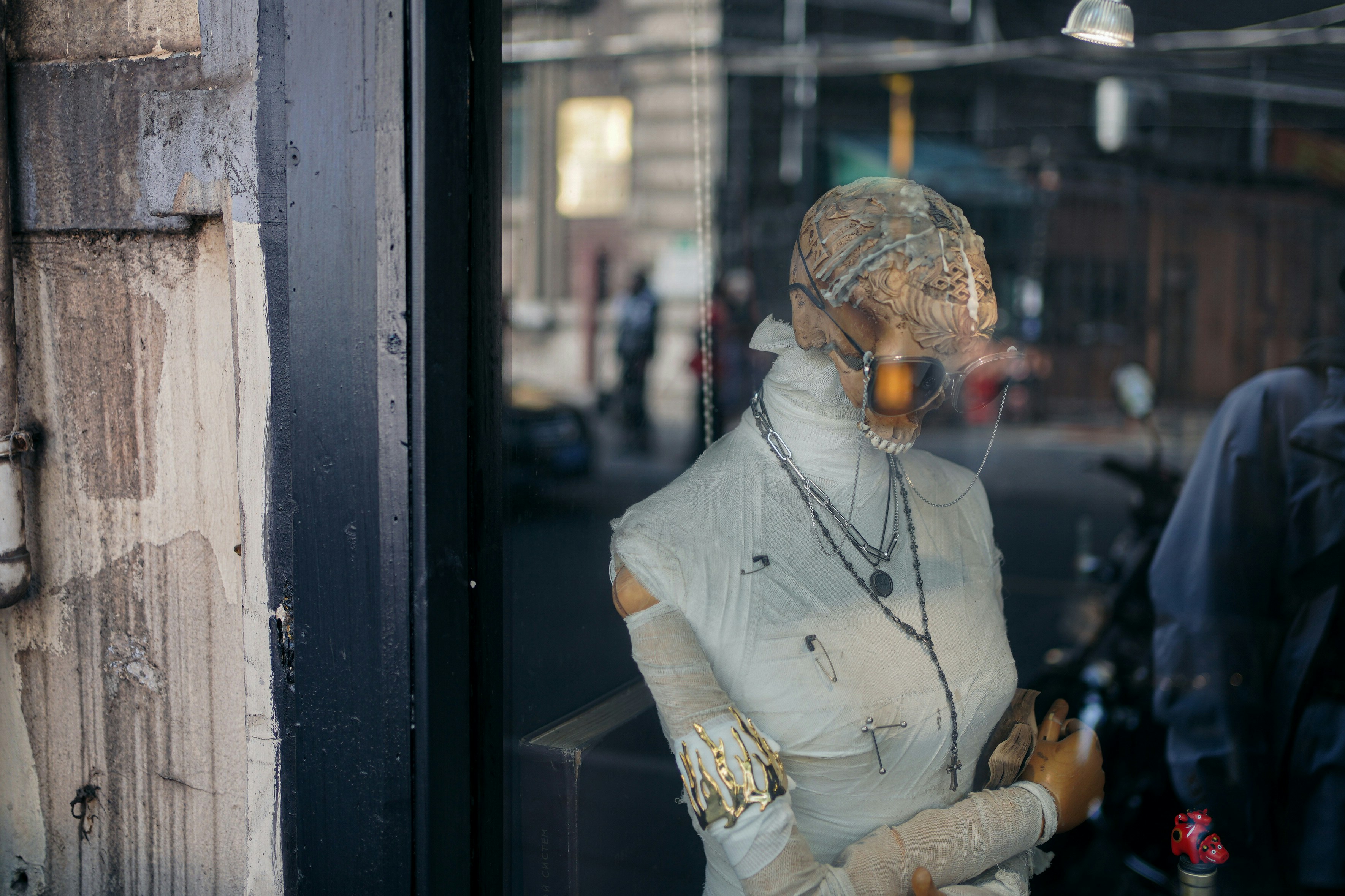 Window Silence: A mannequin poised in a city storefront amid softened reflections