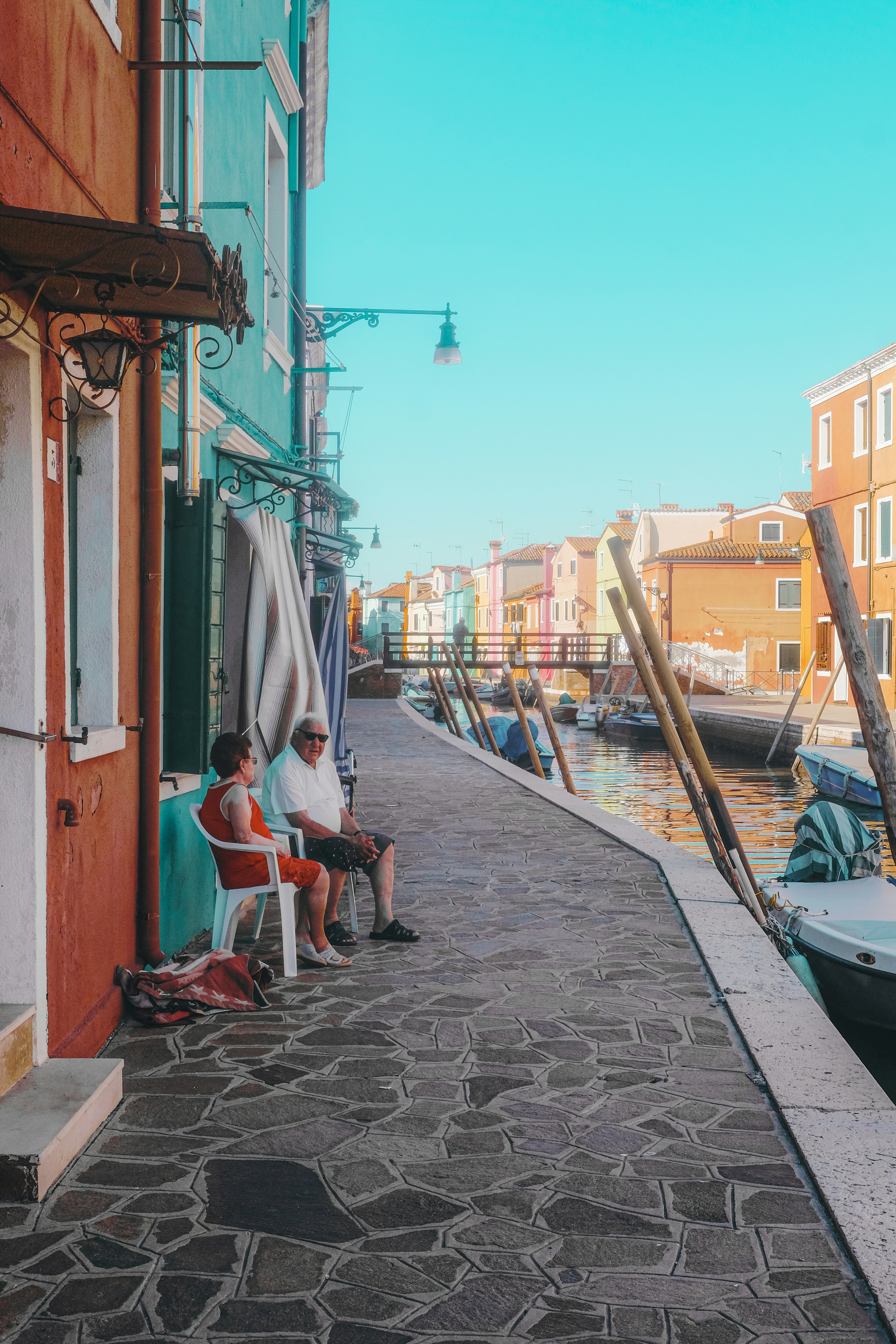 man in blue shirt sitting on chair near blue boat during daytime