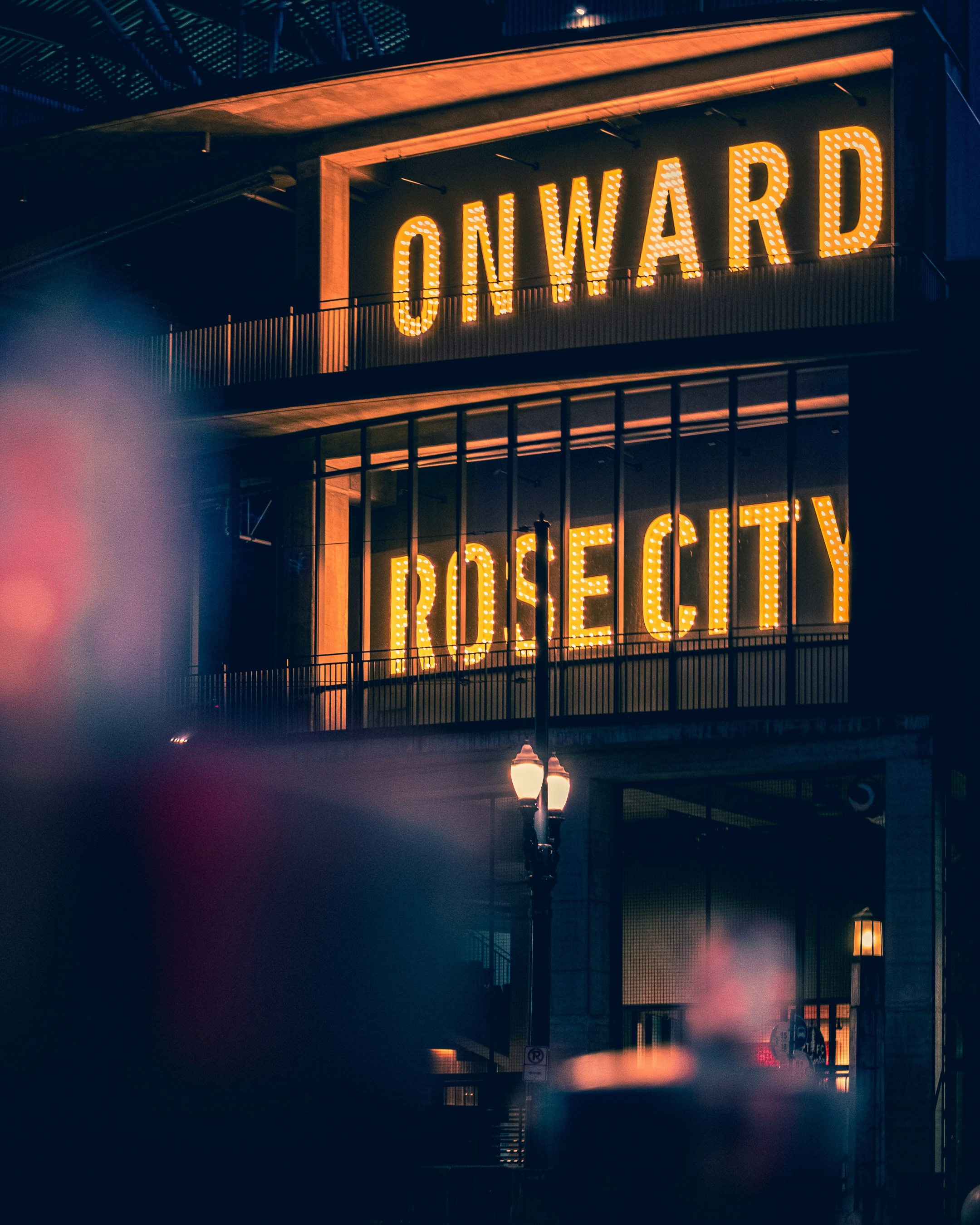 Neon Onward: A Night Street Sign Amid Blurred City Motion