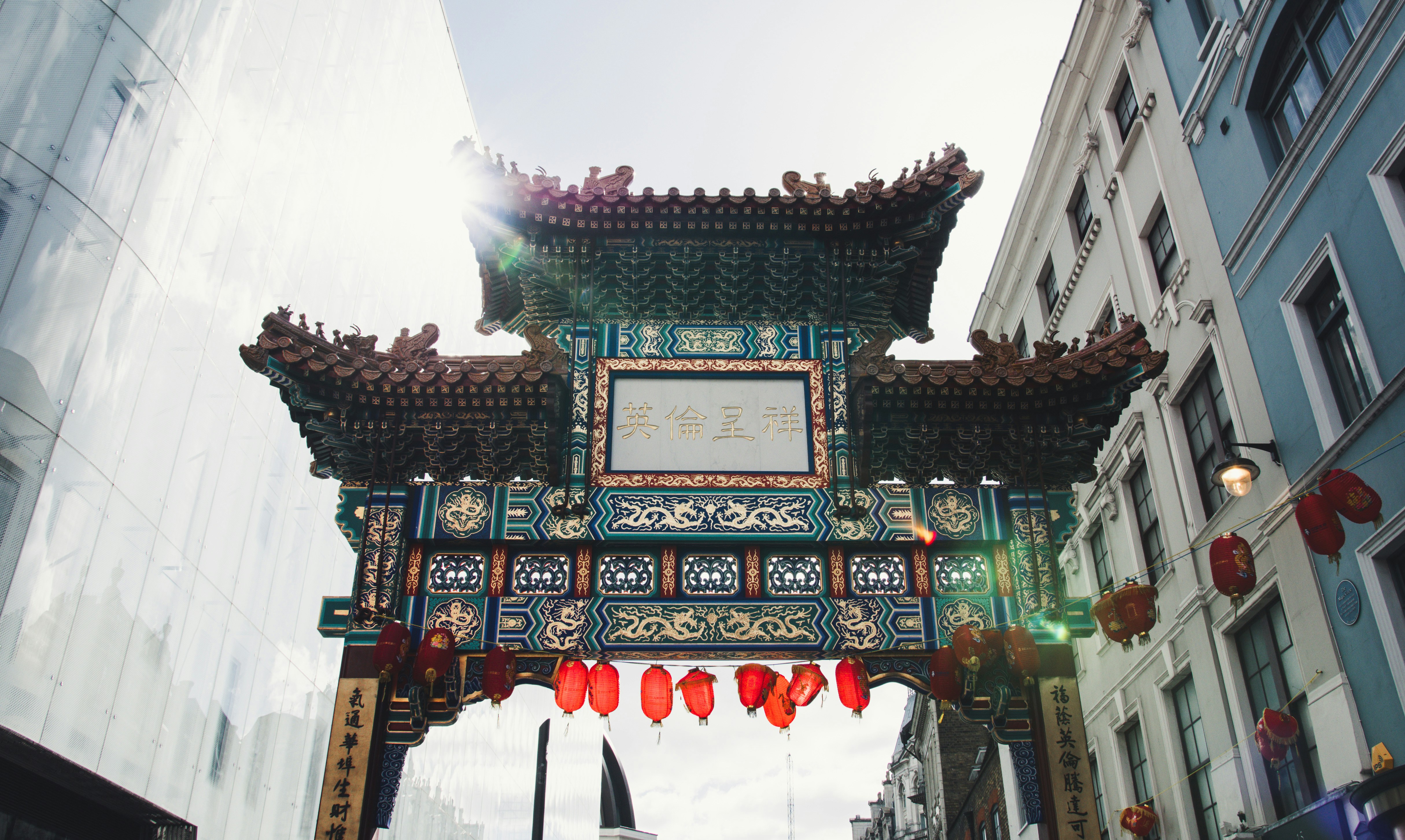 Sunlit Paifang Between Glass Towers: An Ornate Gateway in Modern City Streets