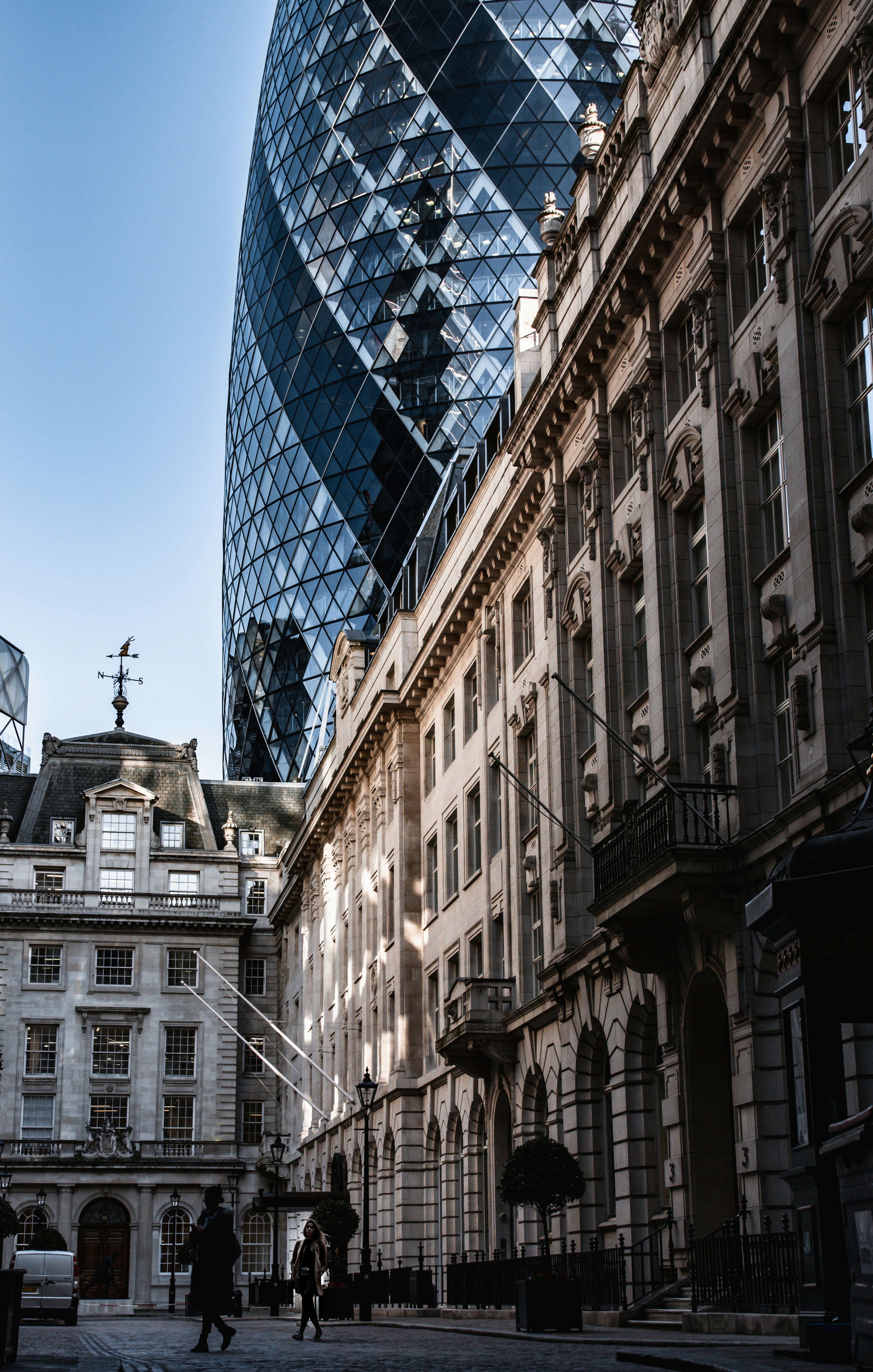 Modern skyscraper reflecting in glass juxtaposed against classic architecture in an urban setting.