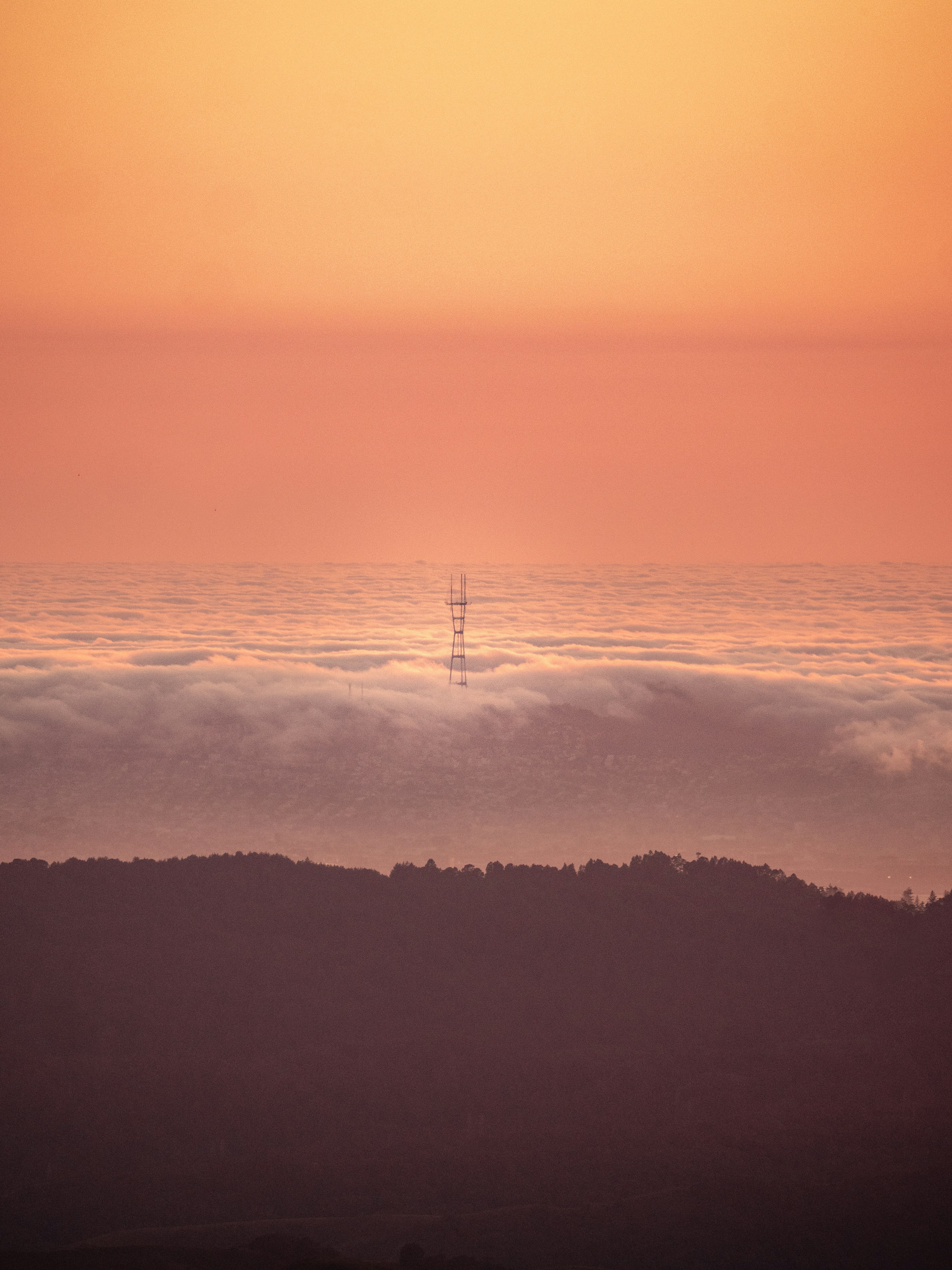 Signal Tower Rising Through a Sea of Clouds at Sunset