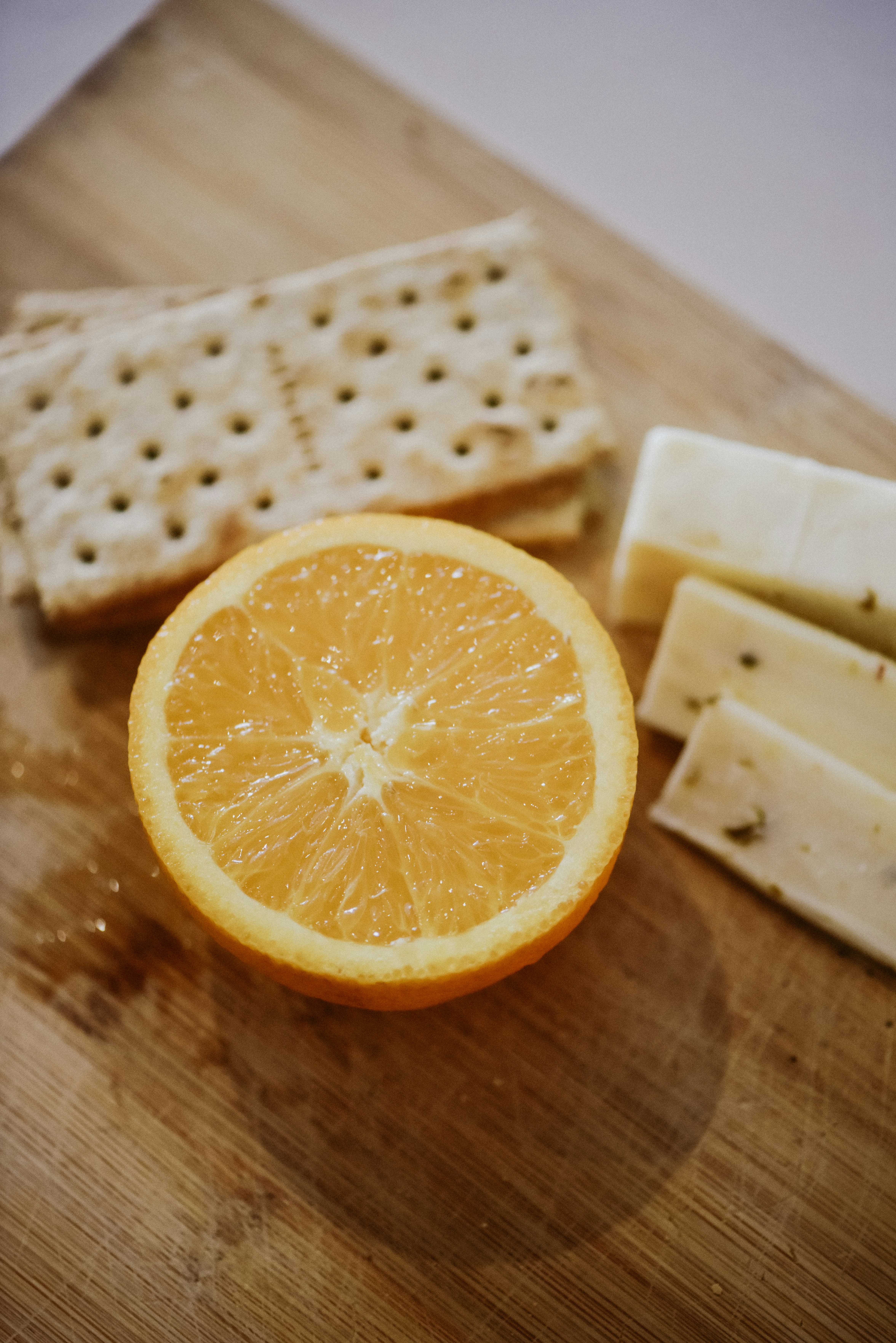 Sliced orange with crackers and cheese on a wooden board.