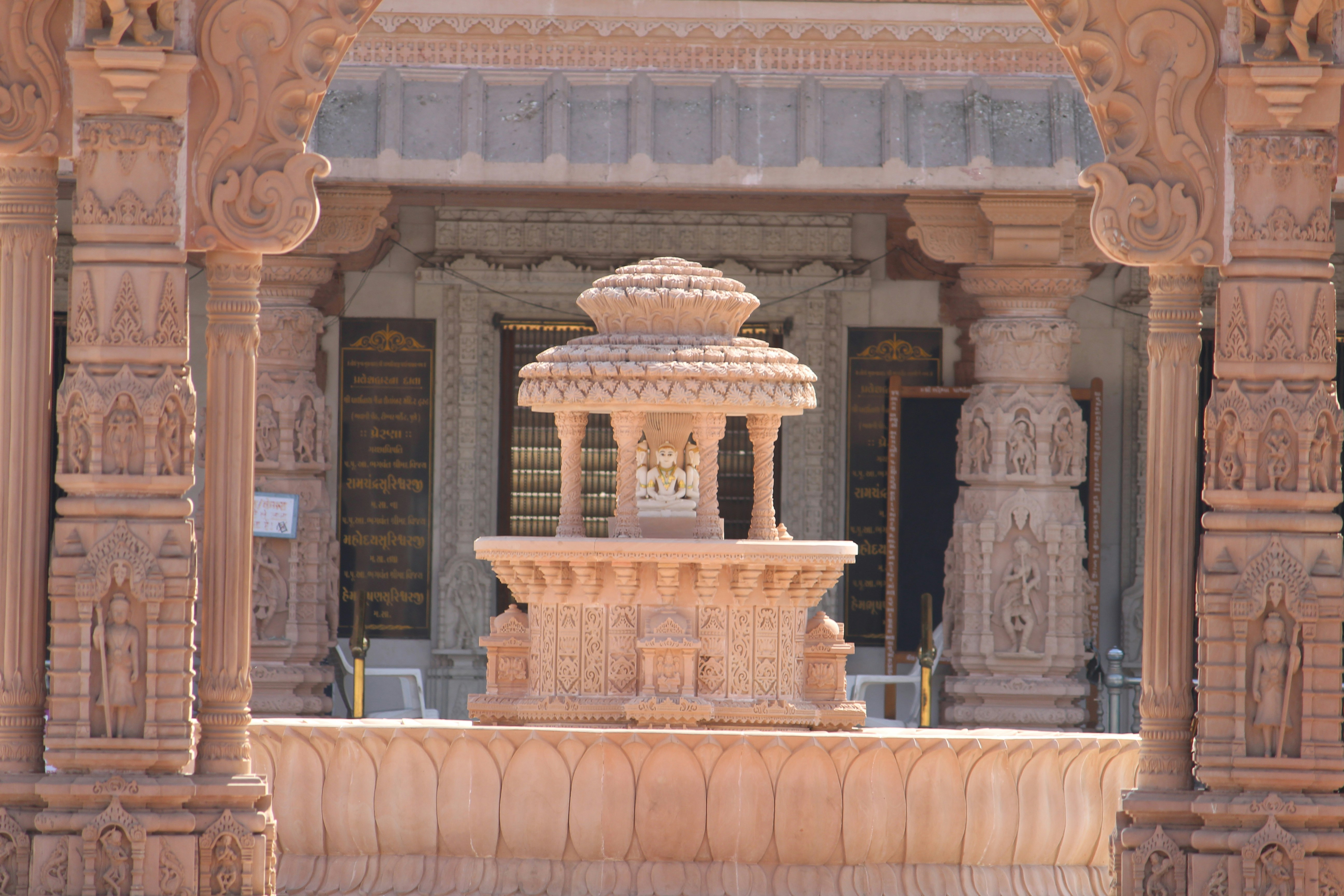Intricately carved fountain surrounded by ornate pillars in a temple courtyard.