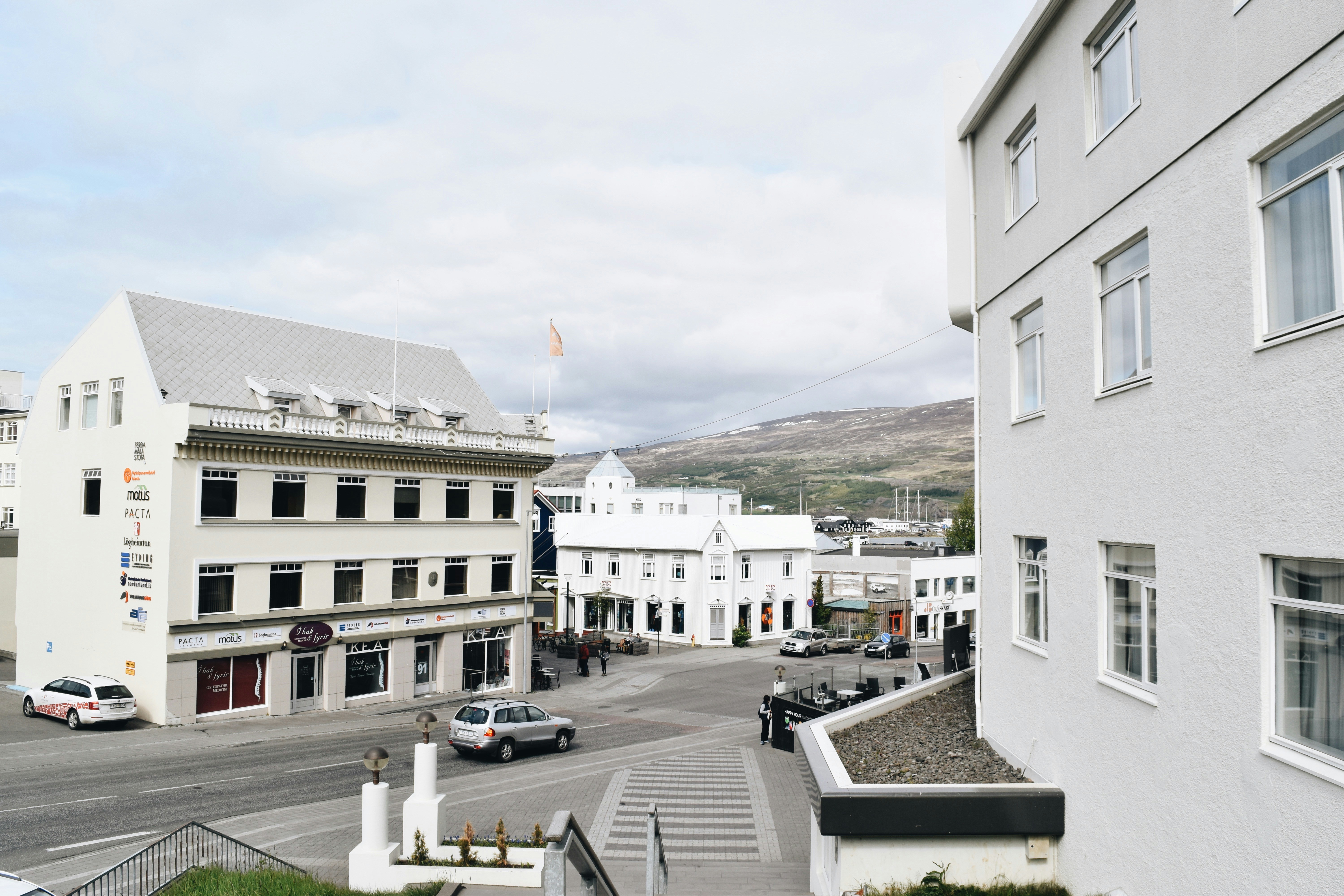 Quiet street scene with white buildings under a cloudy sky in an Icelandic town.
