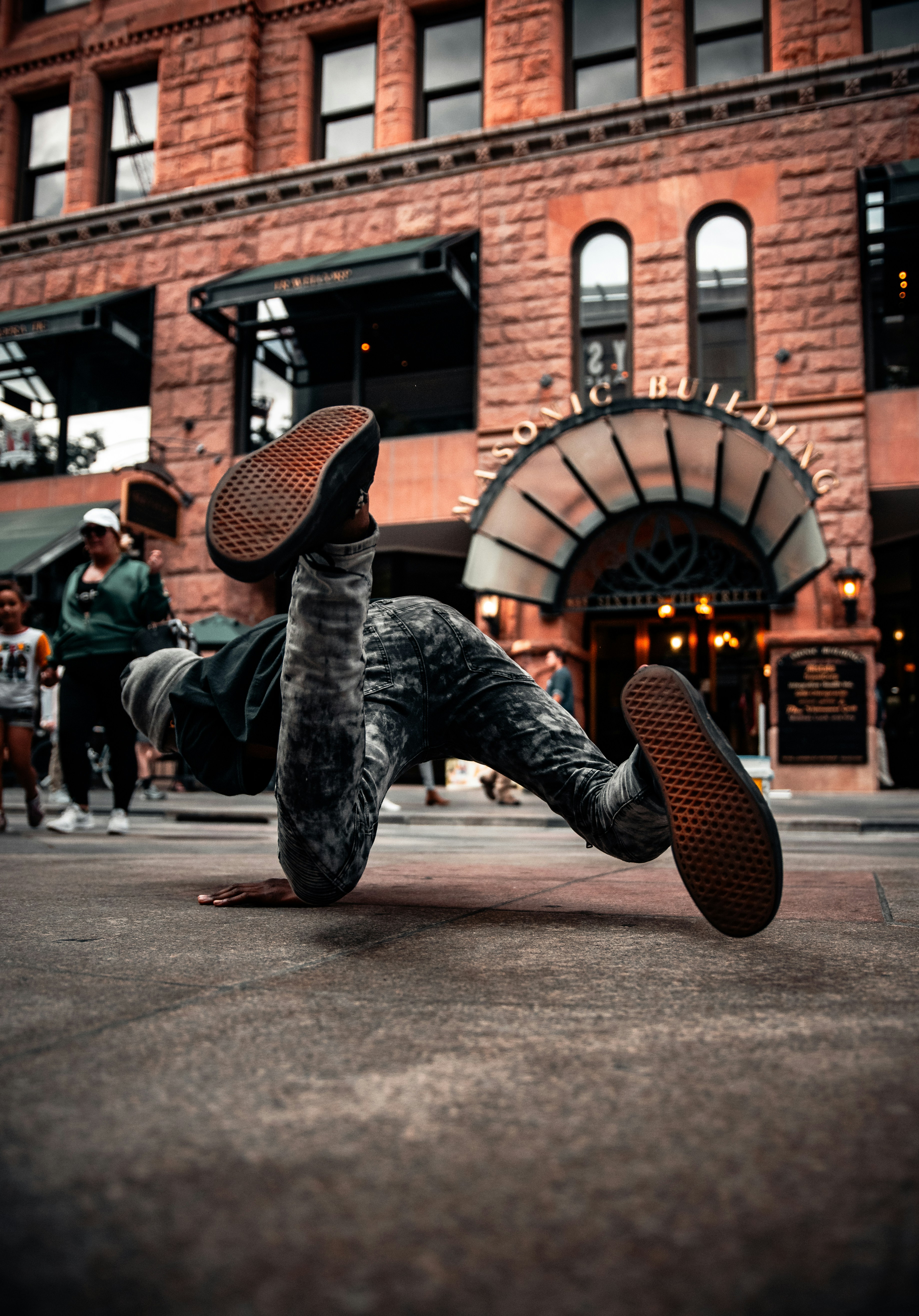 Breakdancer performing a dynamic move on the street in front of a historic building, with onlookers captivated by the action.