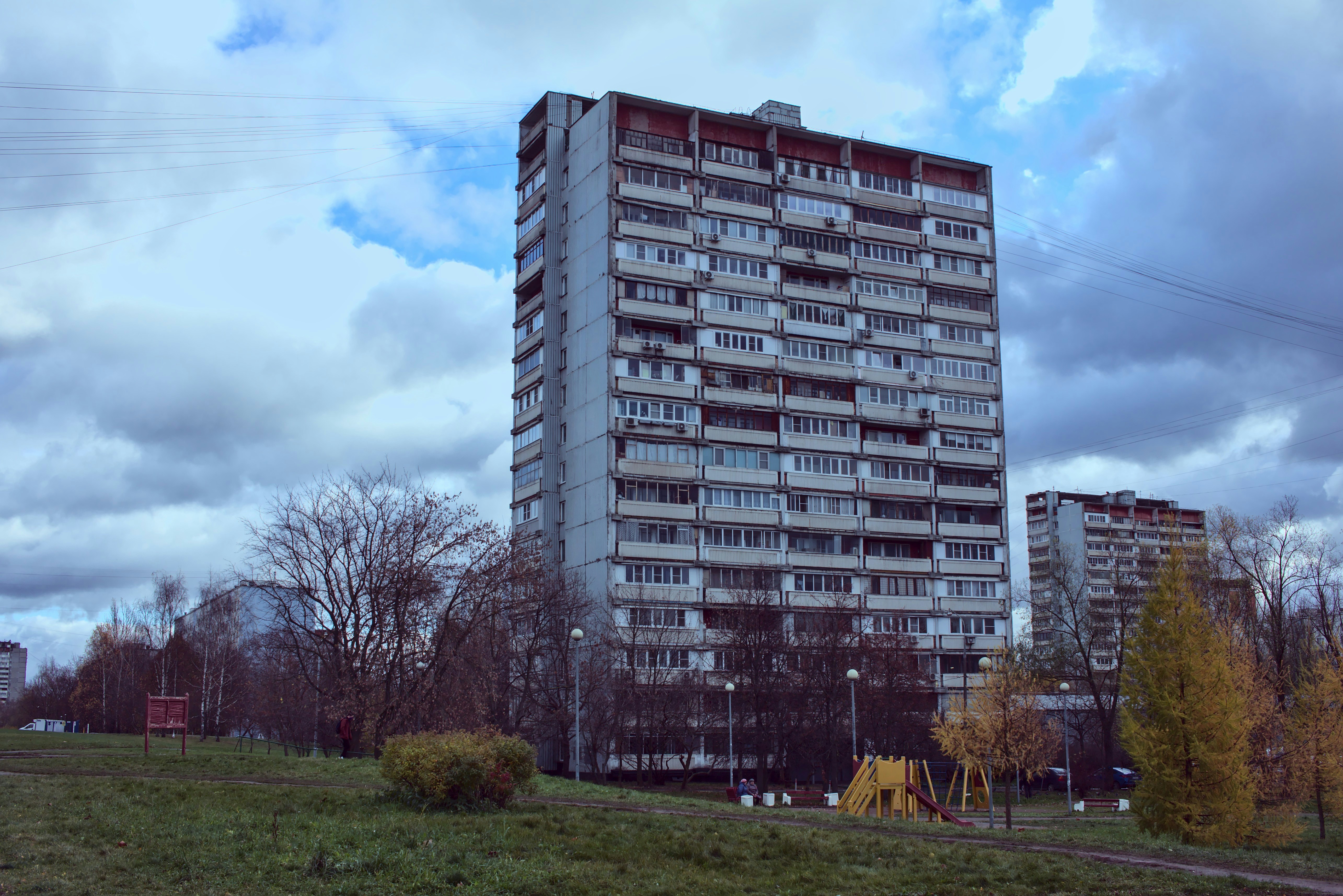 Mid-Rise Apartment Tower Looms Over a Park with Yellow Foliage