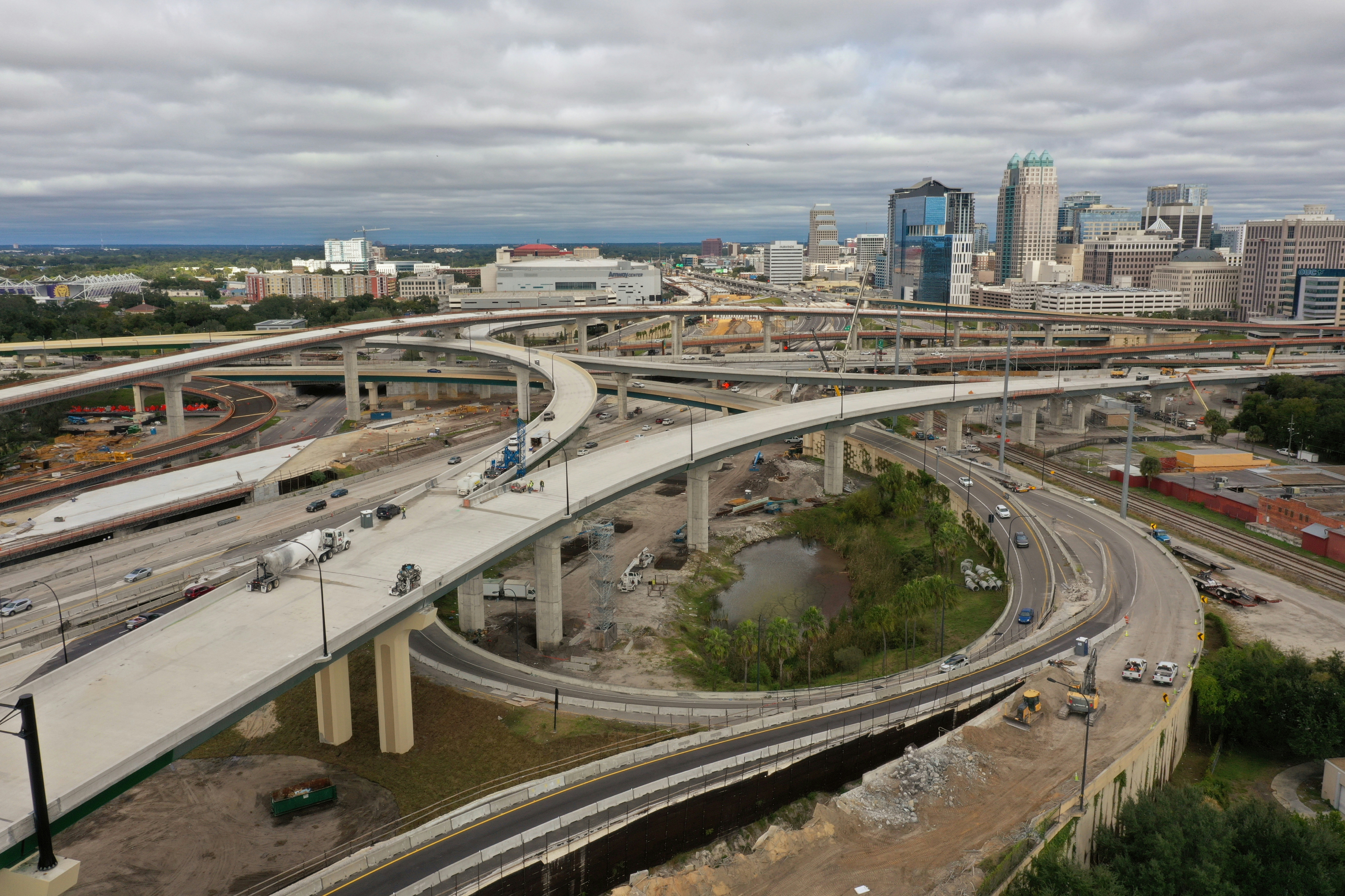 Aerial view of intricate highway construction weaving through a cityscape under a cloudy sky.