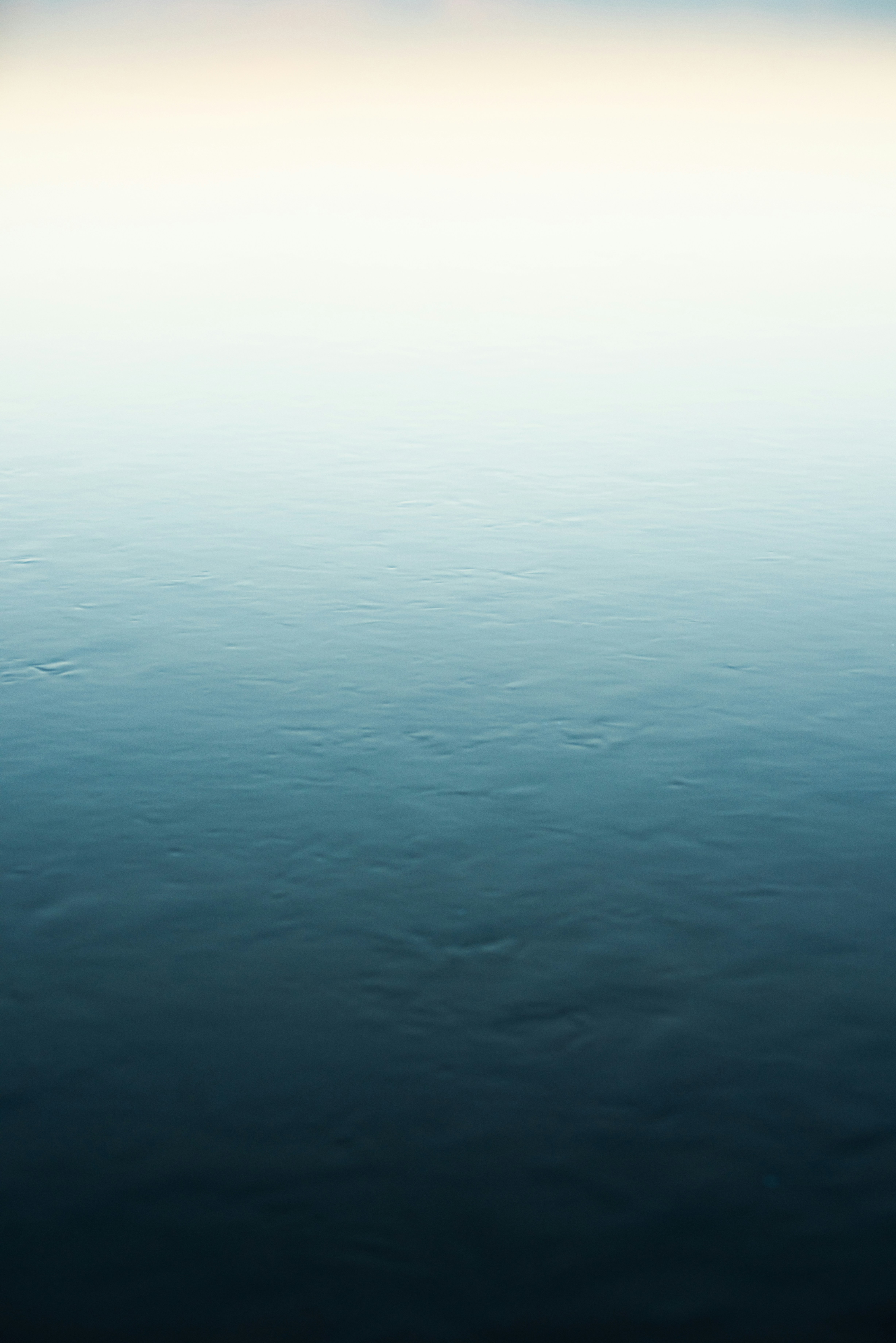 Smooth, reflective water surface blending seamlessly with a soft gradient sky above. The tranquility of the scene invites contemplation.