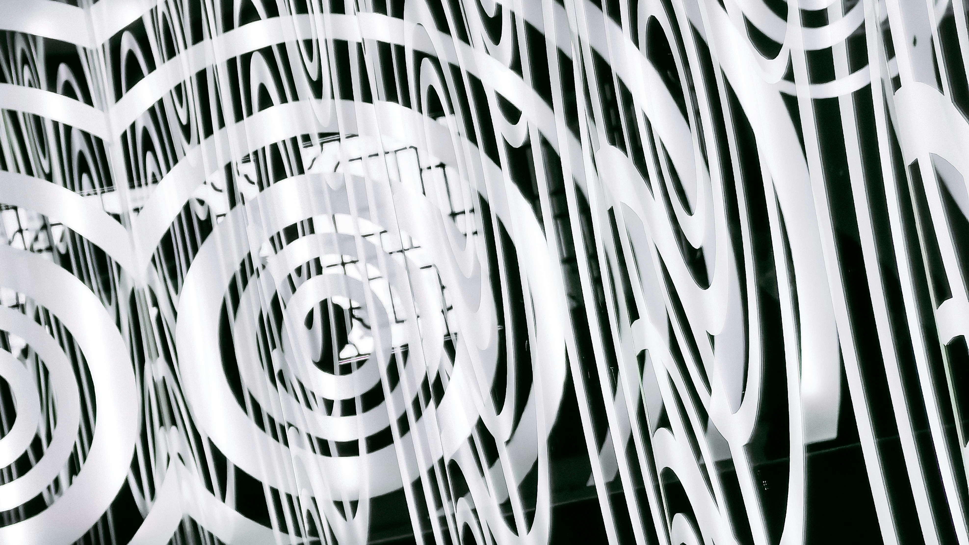 Abstract design featuring swirling patterns of white lines against a dark background, creating a sense of movement and depth.