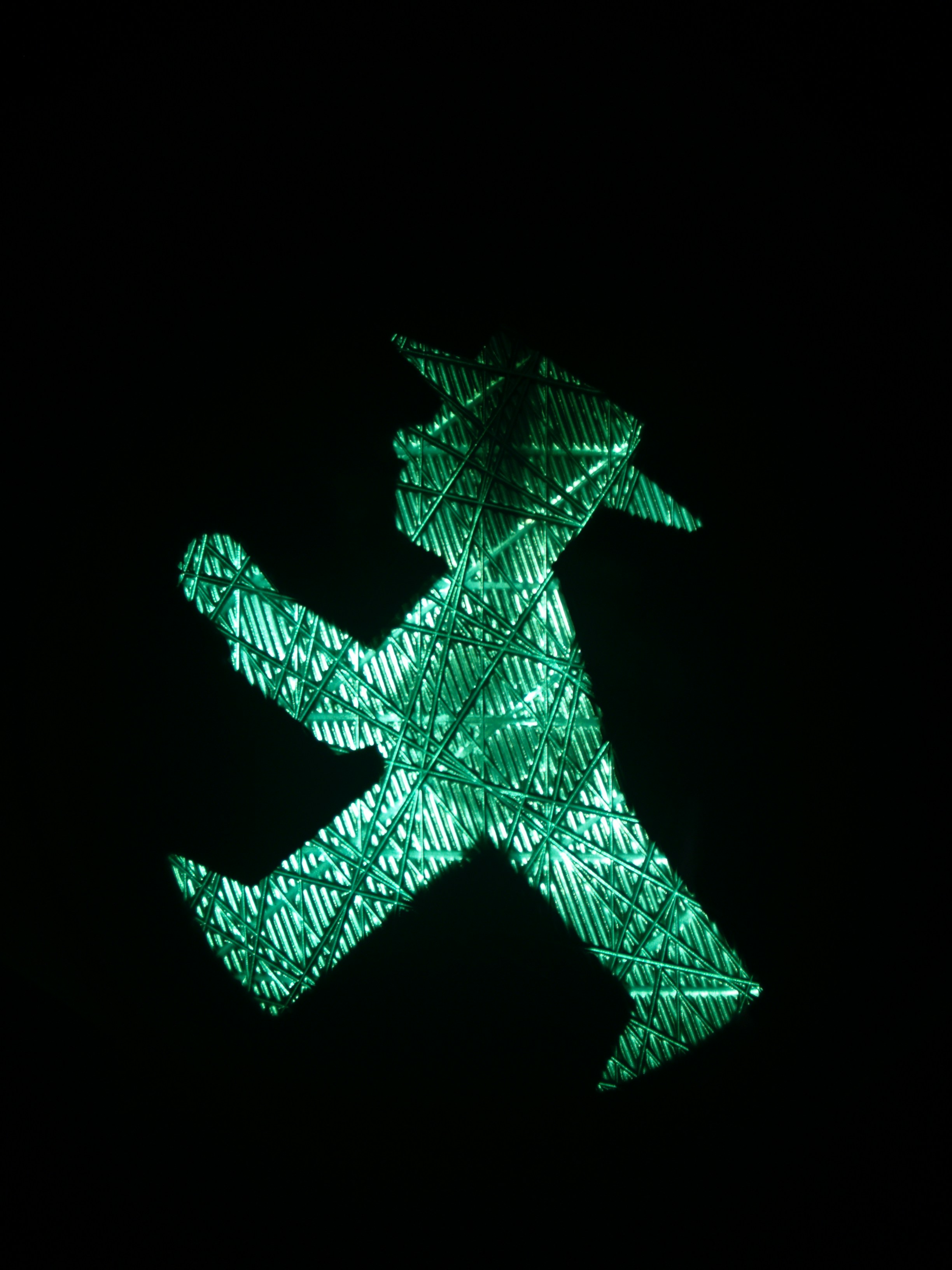 Green lattice sculpture shaped like an X glows against a dark background.