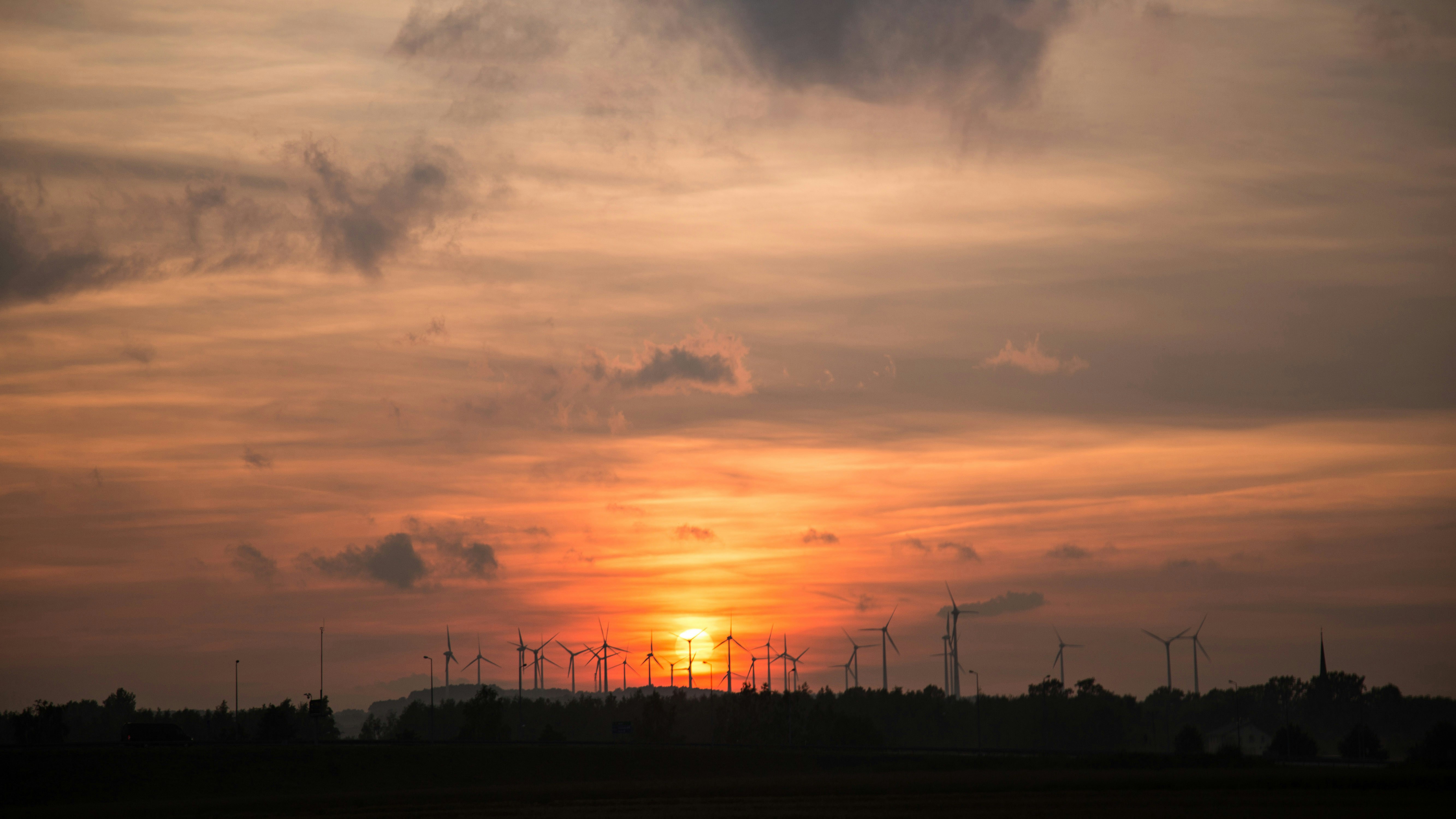 Sunset over a landscape with silhouetted power lines and dramatic clouds.