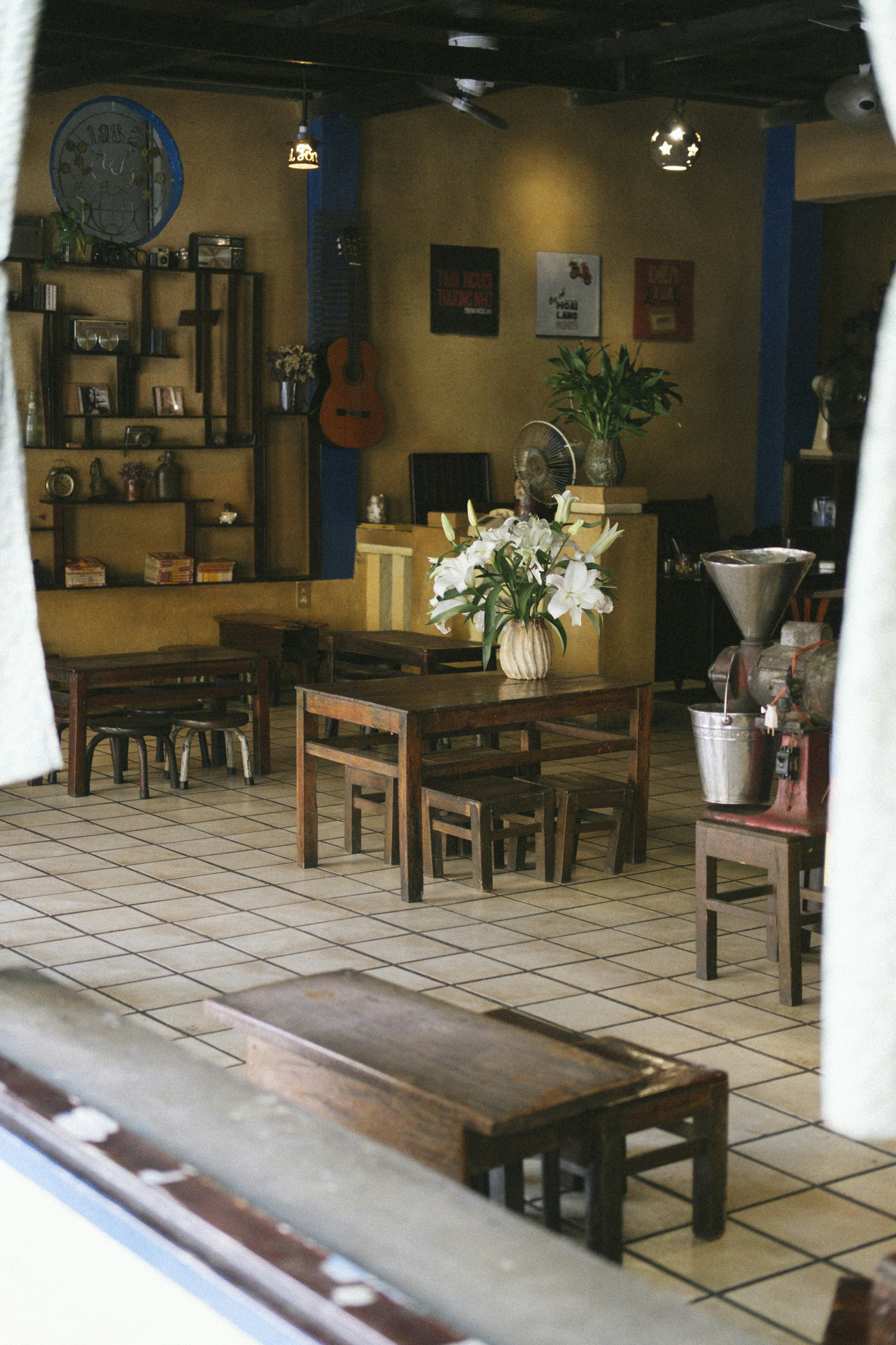 Inviting café interior featuring wooden tables, a flower arrangement, and a warm color palette. The ambiance suggests a perfect spot for relaxation or conversation.