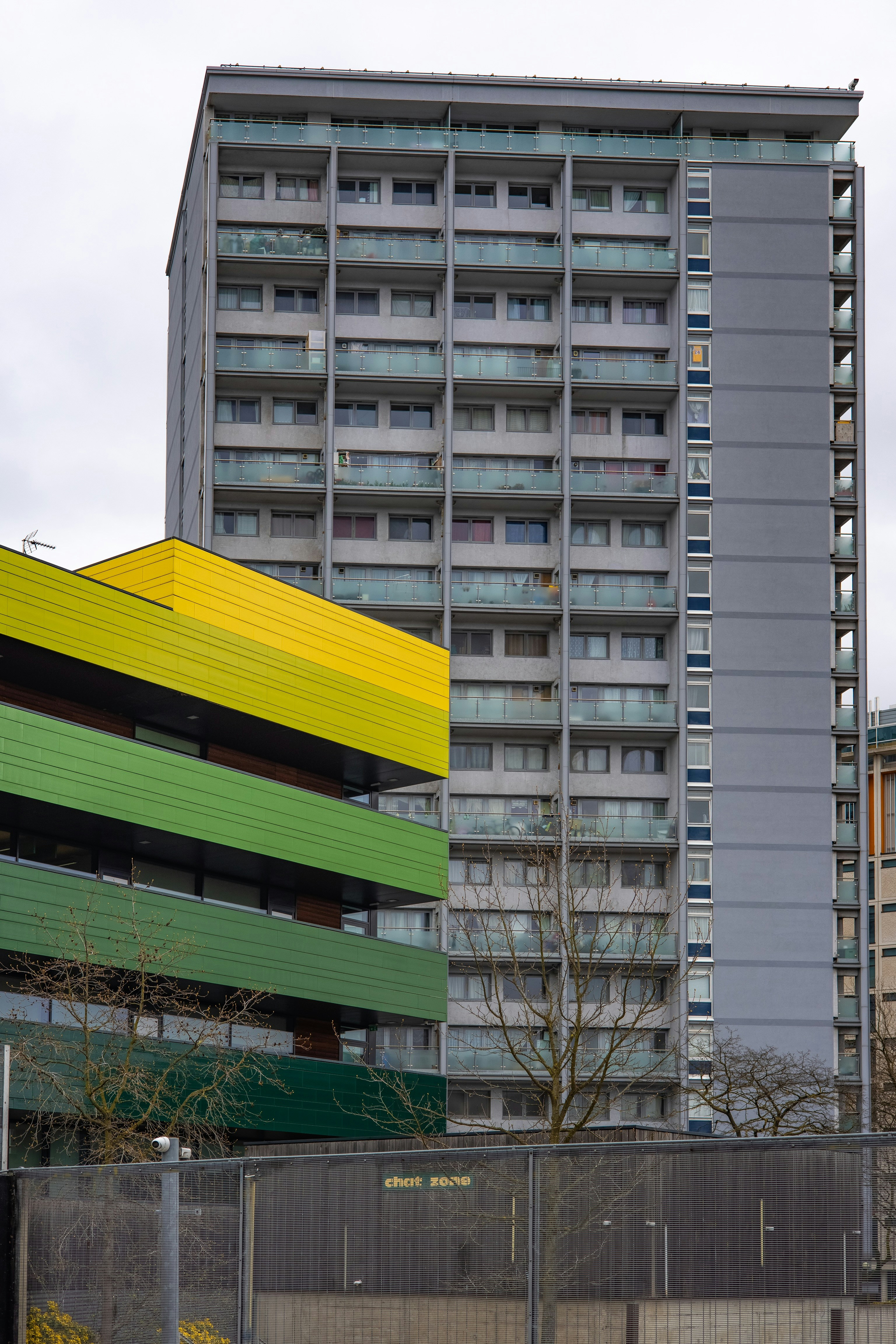 A modern residential building juxtaposed with a vibrant green and yellow architectural design, highlighting urban aesthetics and contemporary living.