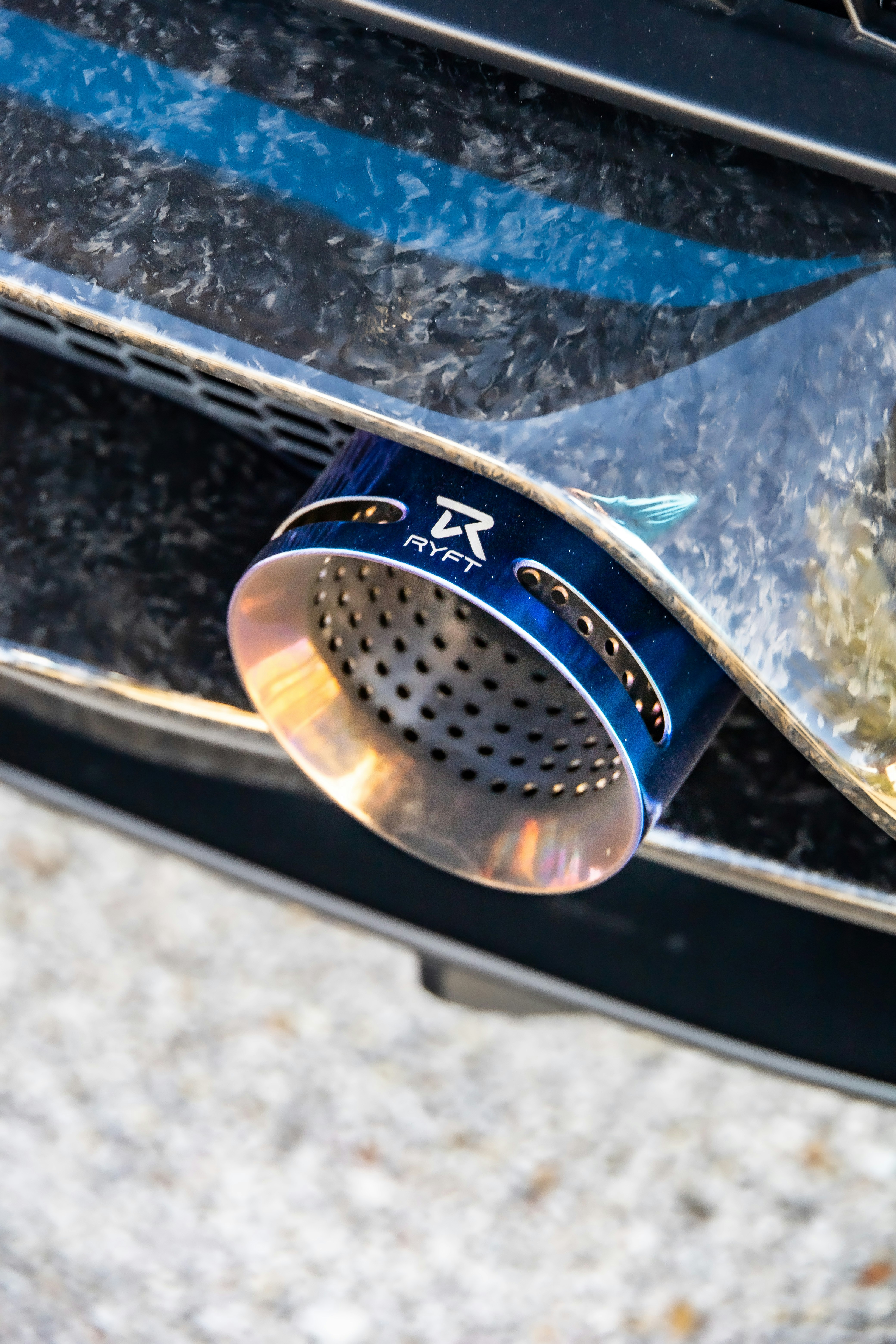 Blue Ryft Exhaust Tip: Close-Up of Perforated Metal Amid Mud and Gloss