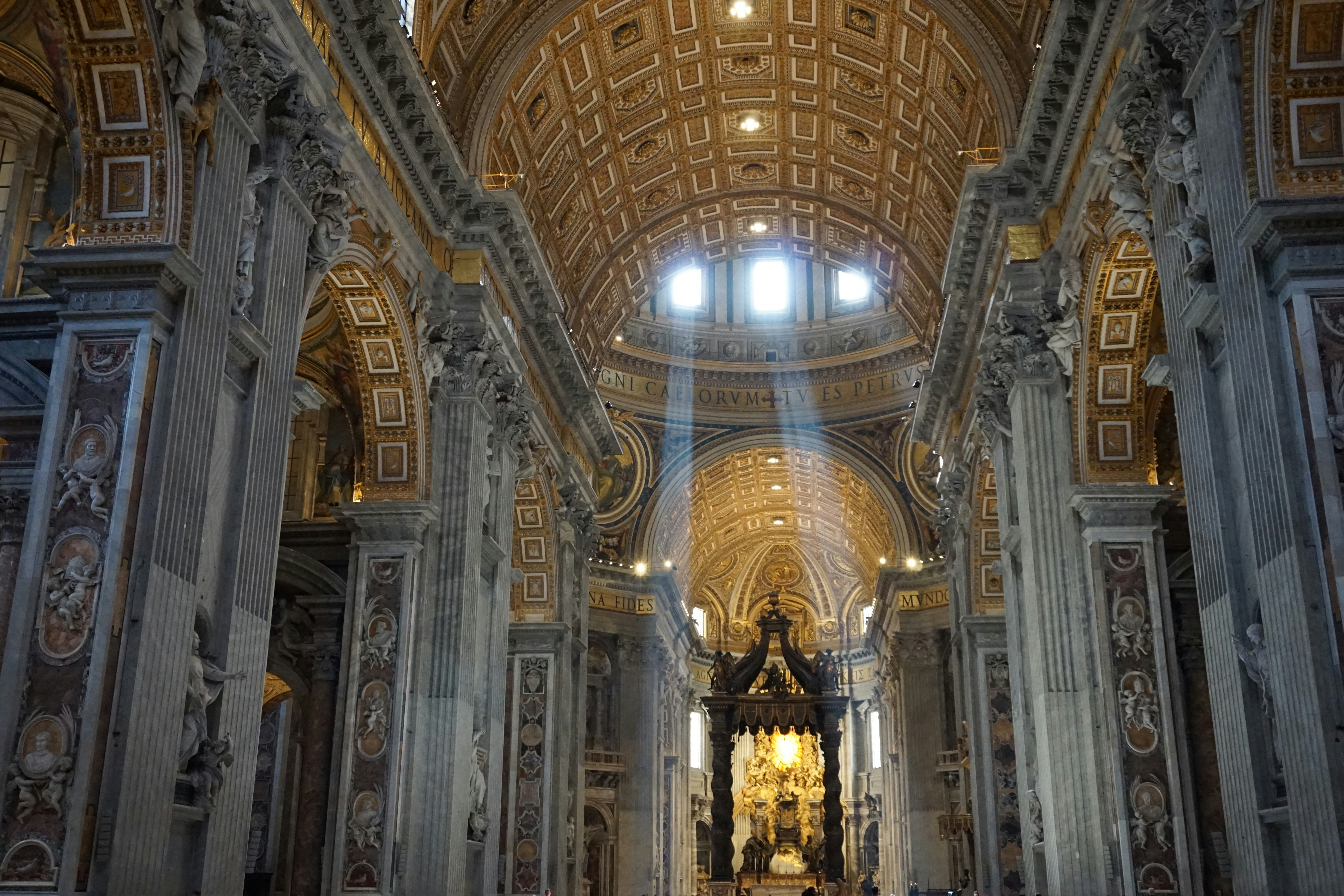 Sunbeams illuminate the ornate interior architecture of St. Peter's Basilica, highlighting intricate designs and towering columns.