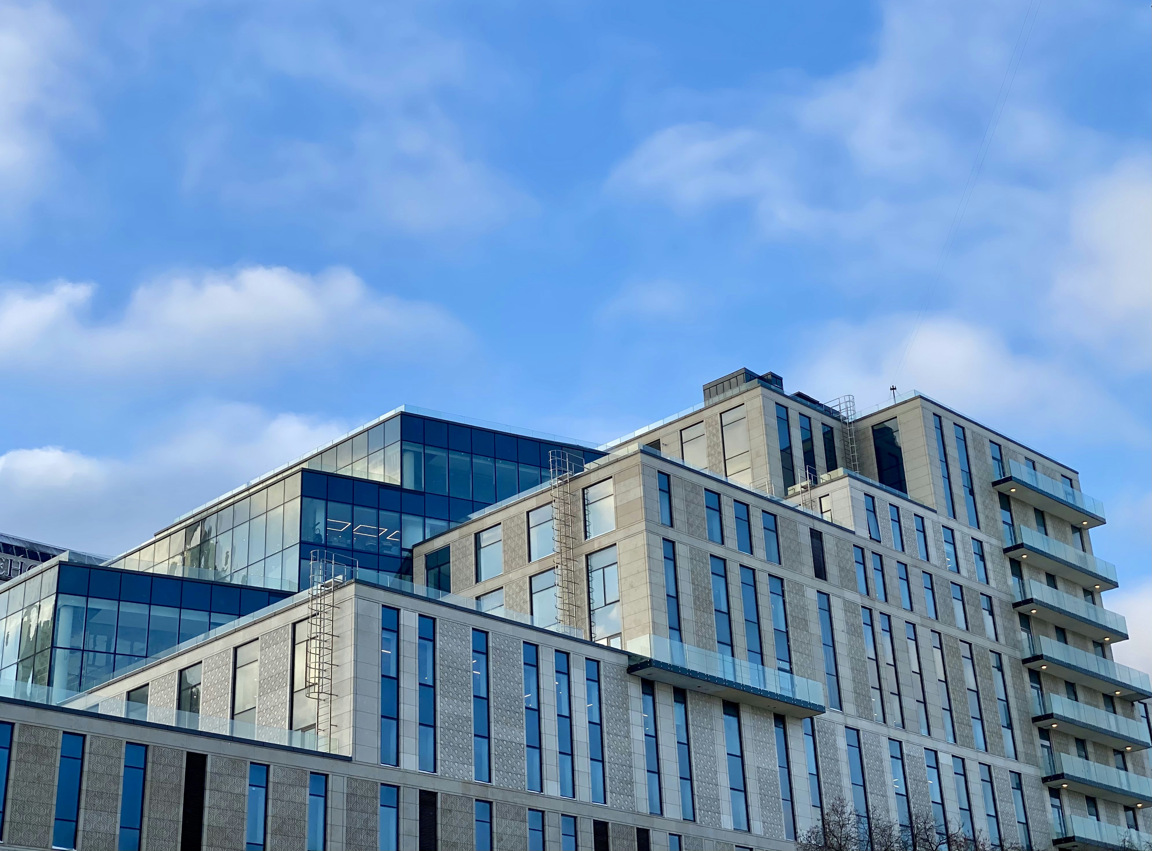 Contemporary building with a mix of glass and stone facades under a blue sky, showcasing modern design elements.