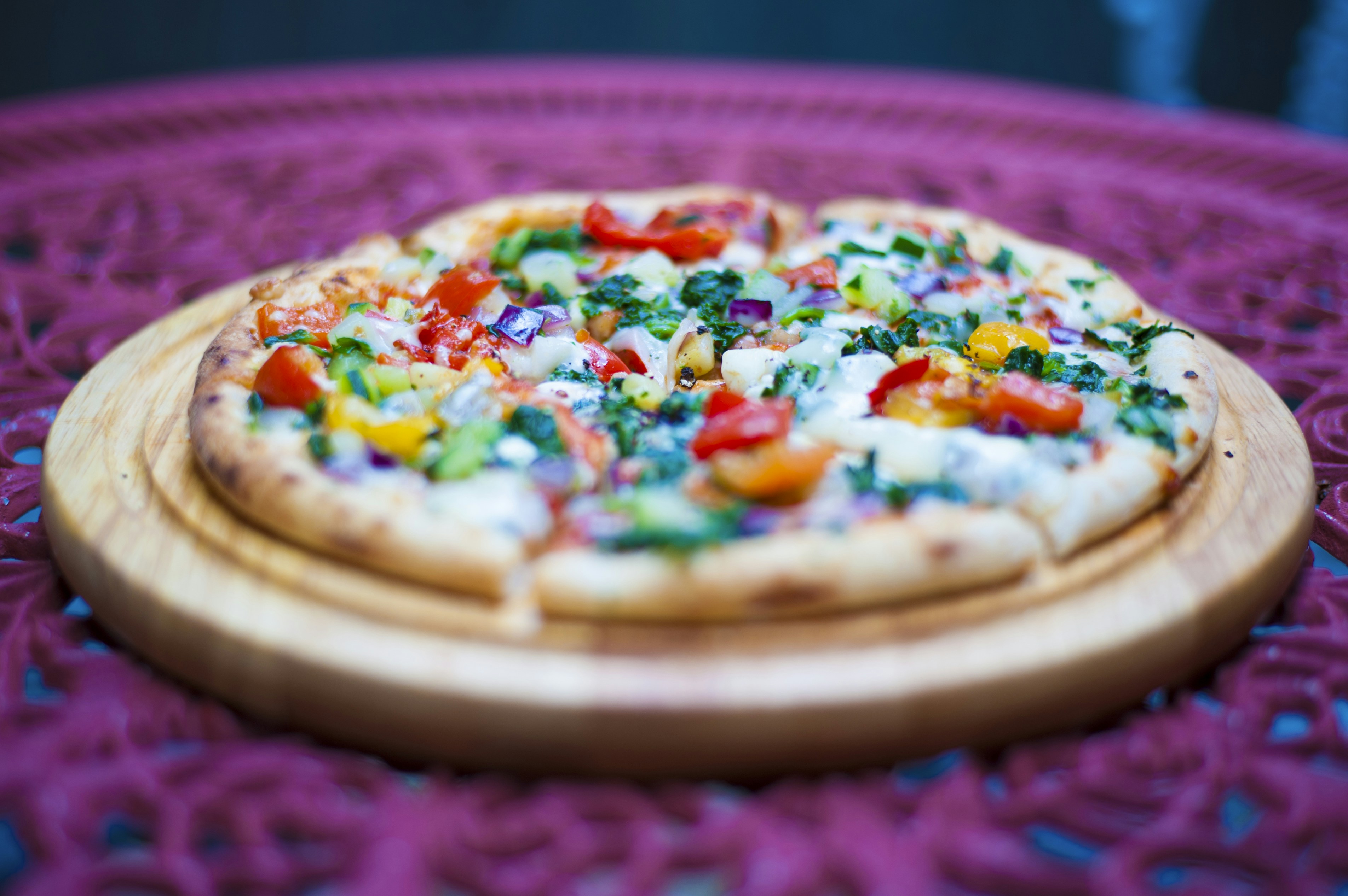Vivid Veggie Pizza on a Wooden Board Framed by Magenta Lace