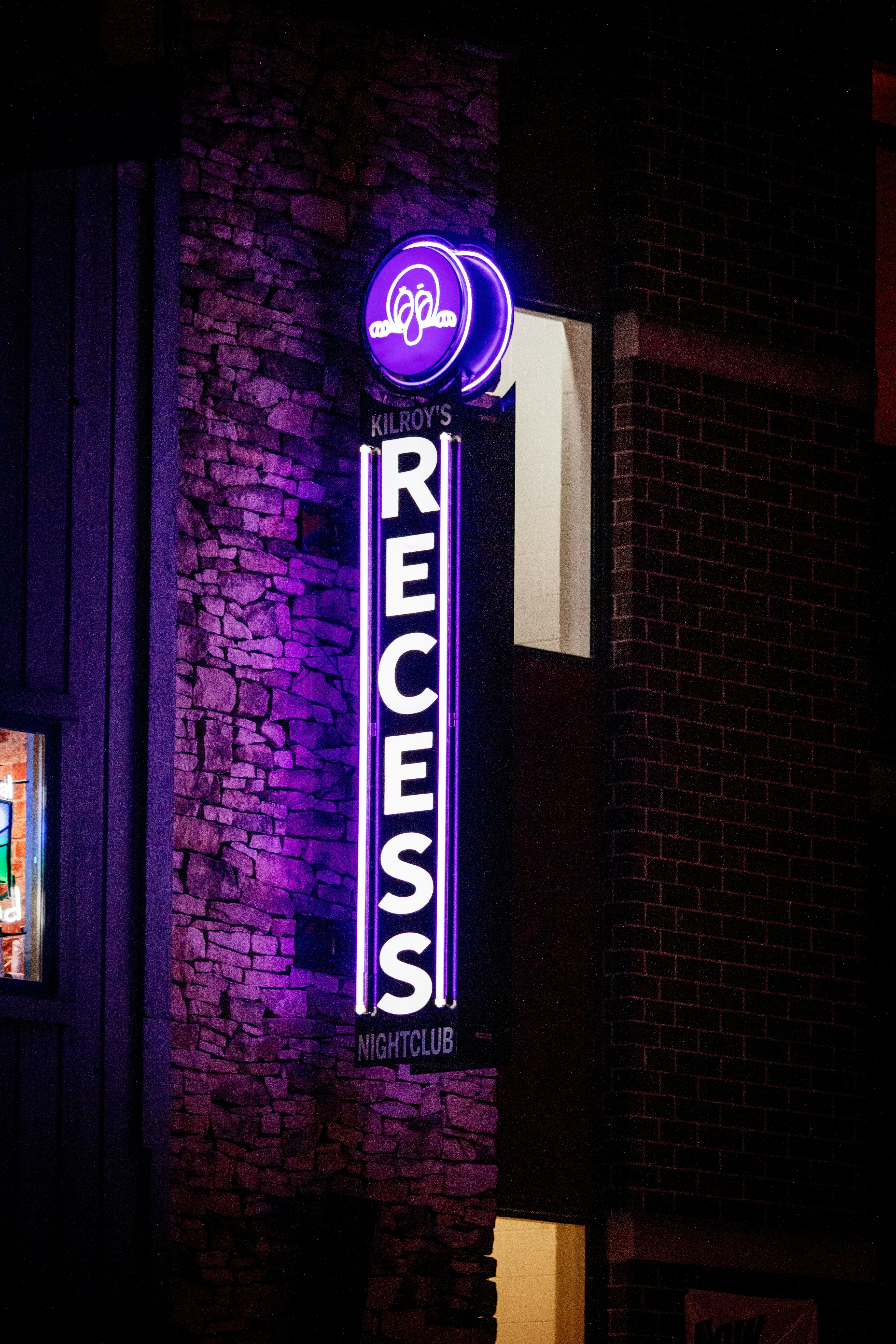 Kilroy's Neon Ice Sign Illuminates a Stone Facade with Purple Night Pulse