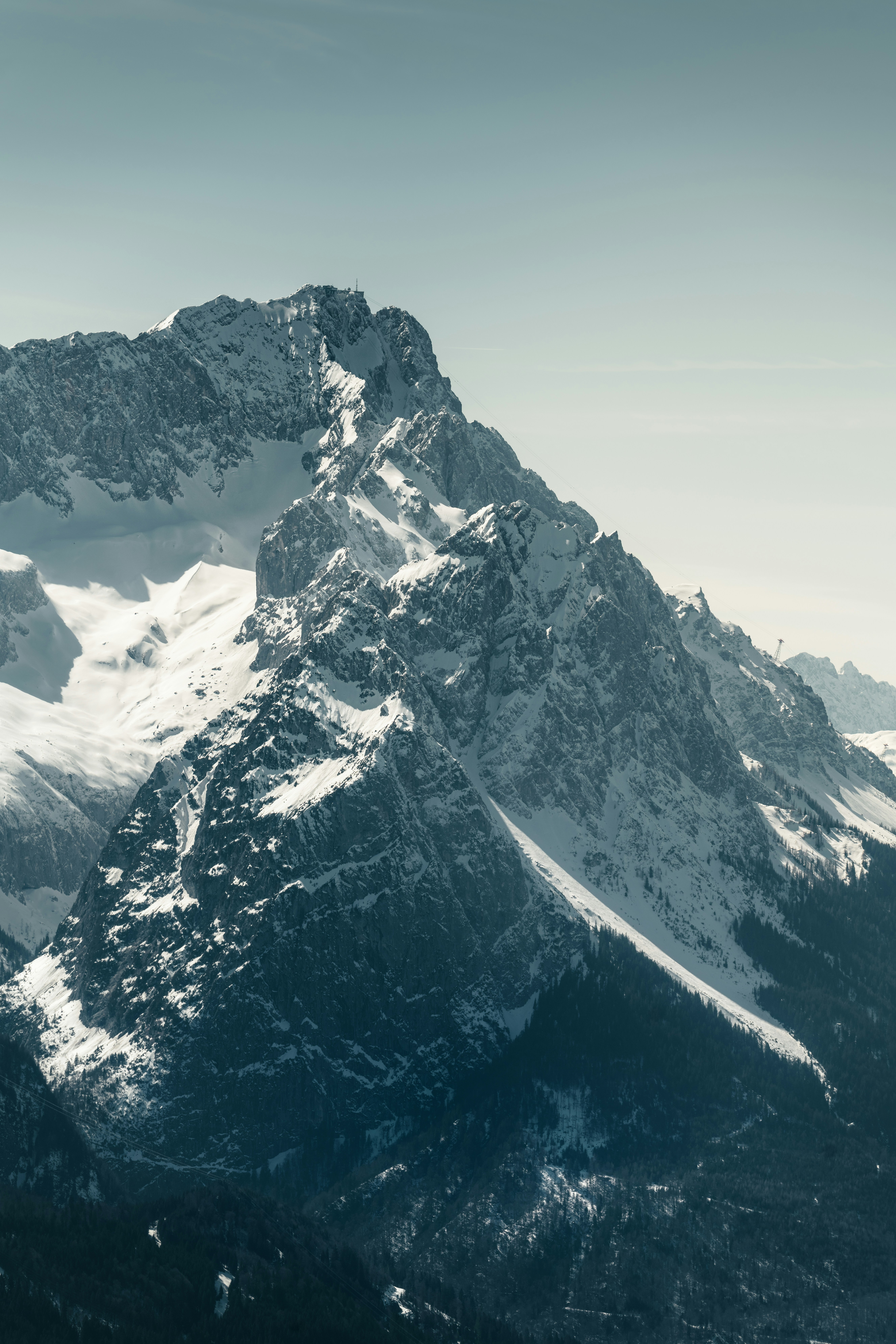 Snow-capped mountain range under a clear sky, showcasing rugged terrain and dramatic cliffs.