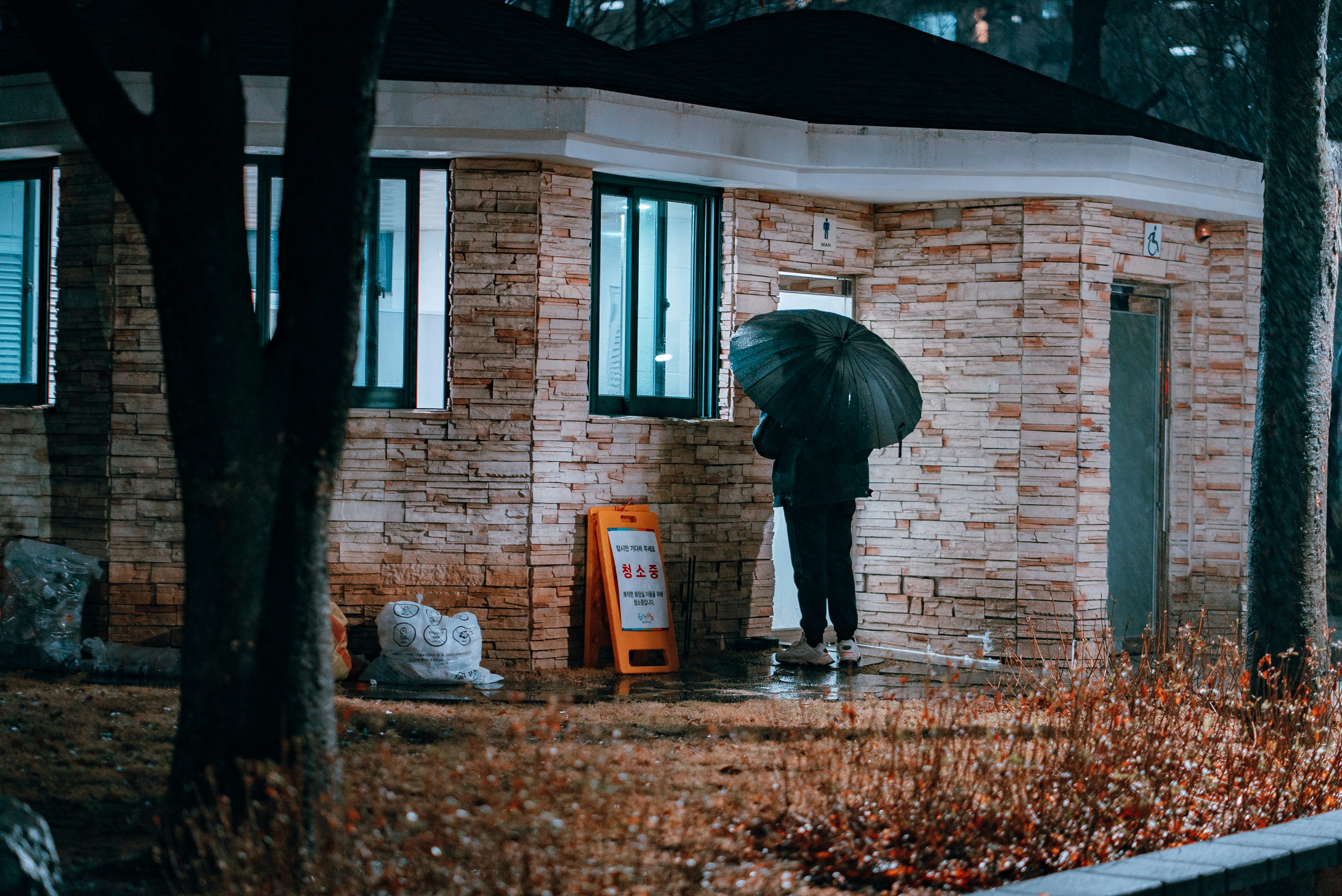 Umbrella Quiet: A Late-Shift Portrait by the Brick-Walled Station