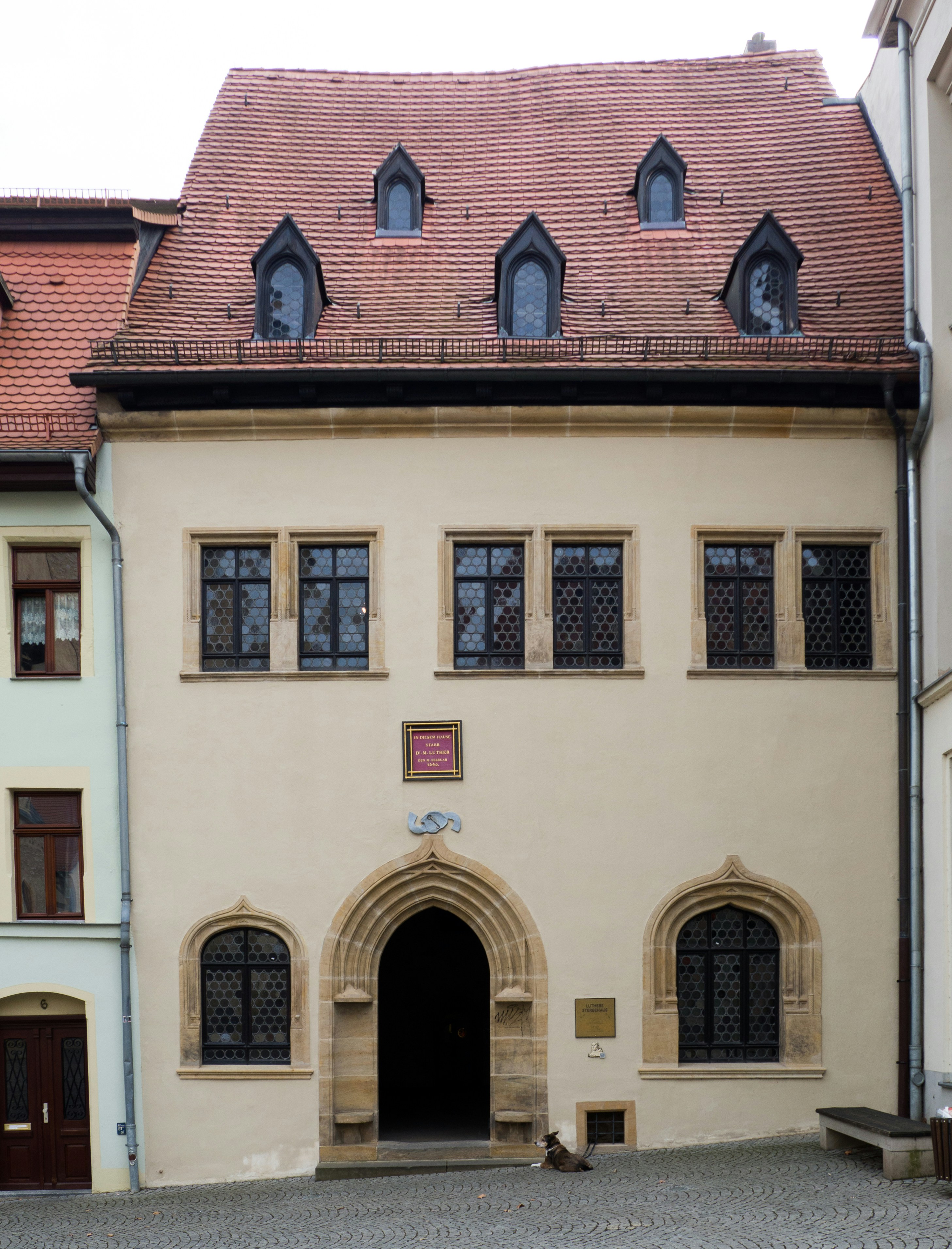 Central Portal under a Red Roof: Gothic Arches on a Pale European Facade