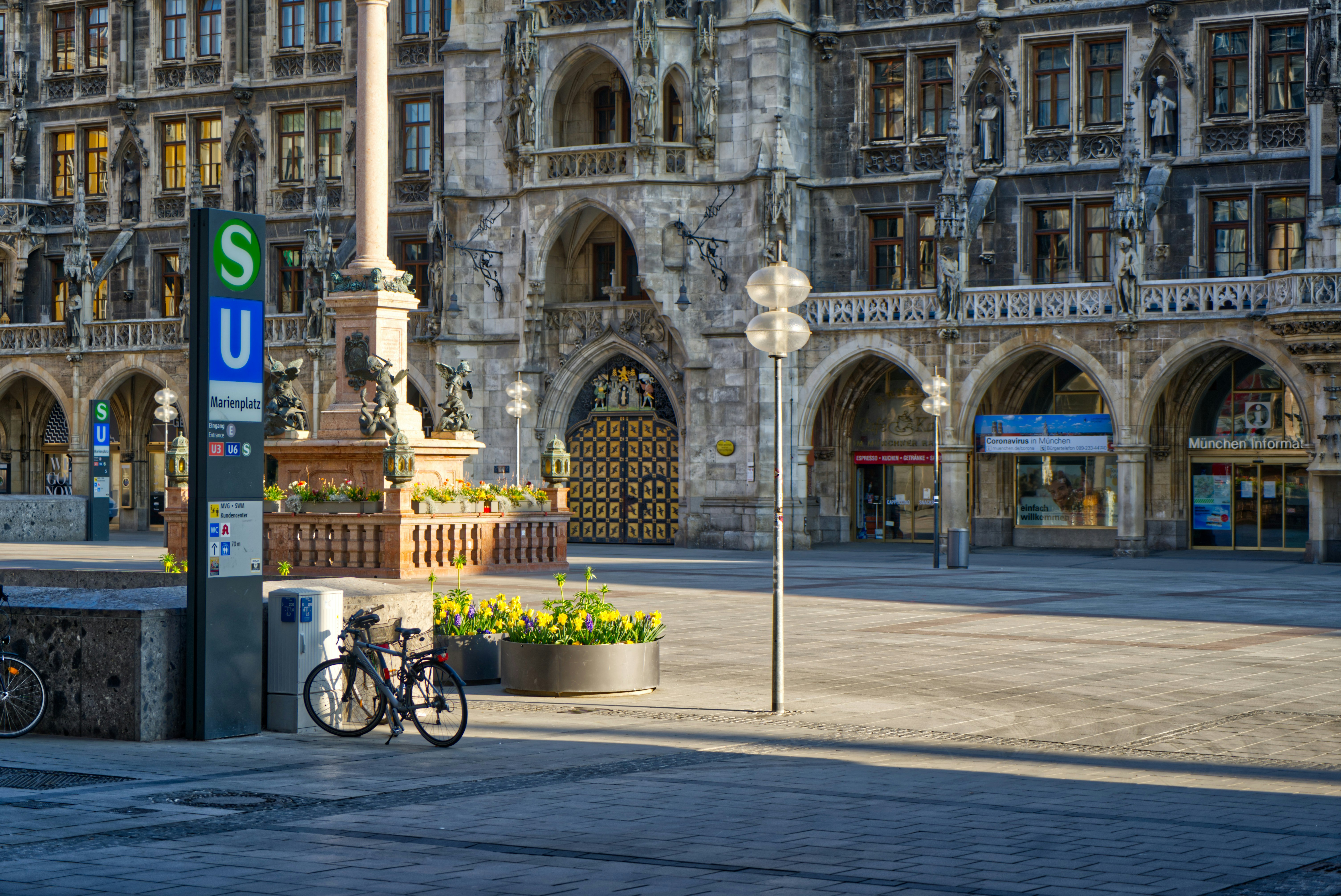 Sunlit square with intricate stone architecture and a solitary bicycle leaning against a signpost.