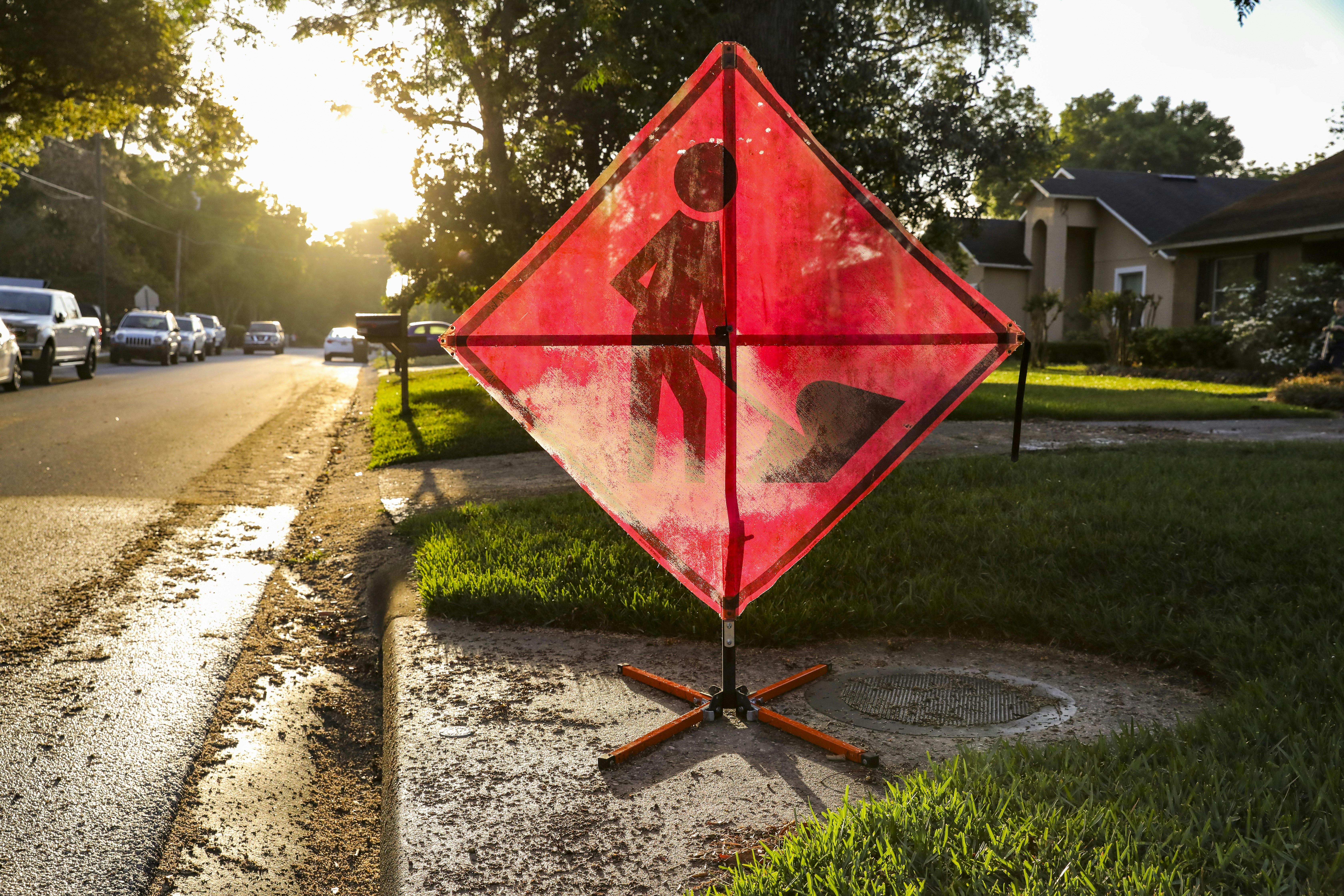 Sunlit Suburban Barrier: A translucent caution sign anchors a quiet street