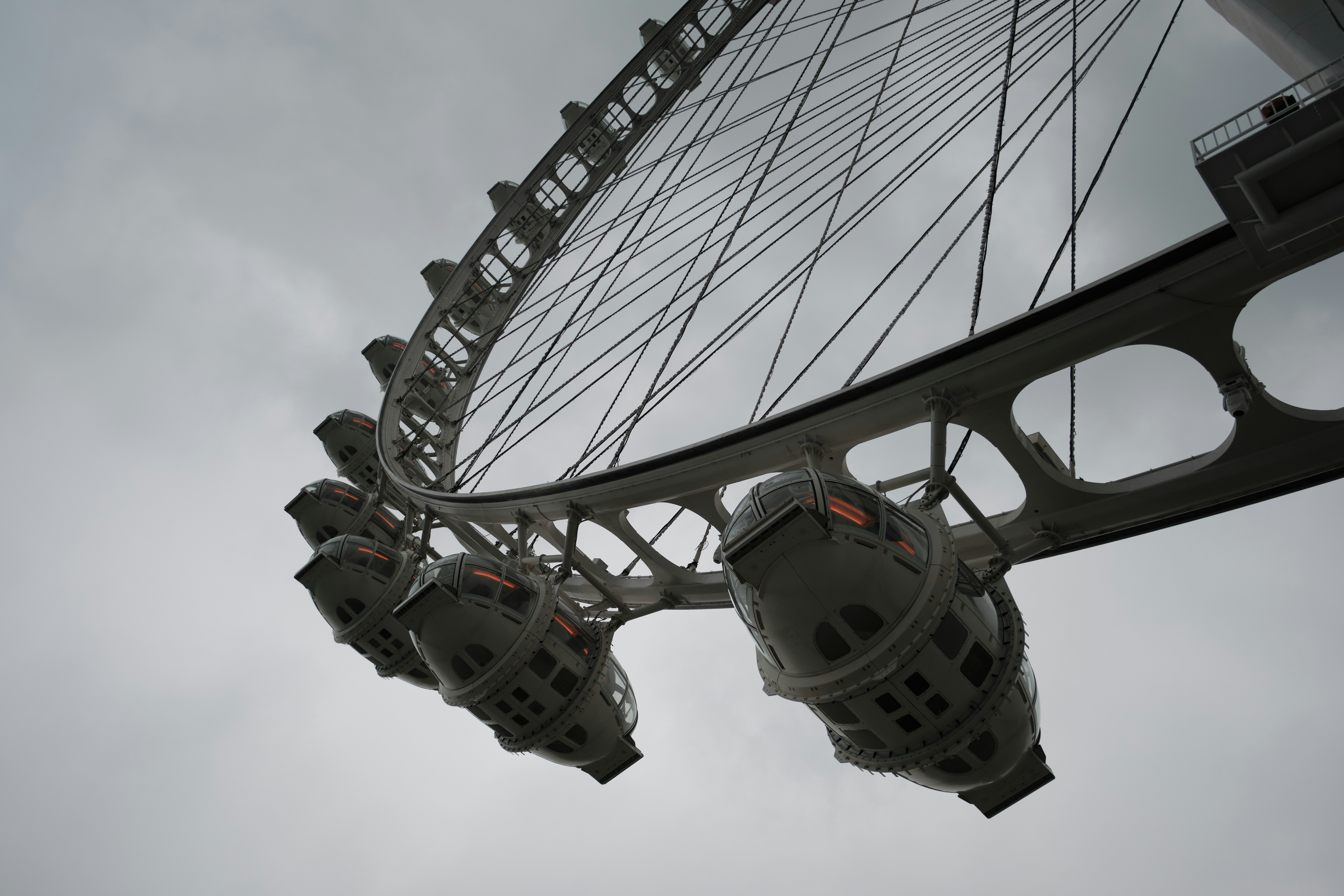 A close-up view of a Ferris wheel's gondolas against a cloudy sky, showcasing its intricate structure and design.