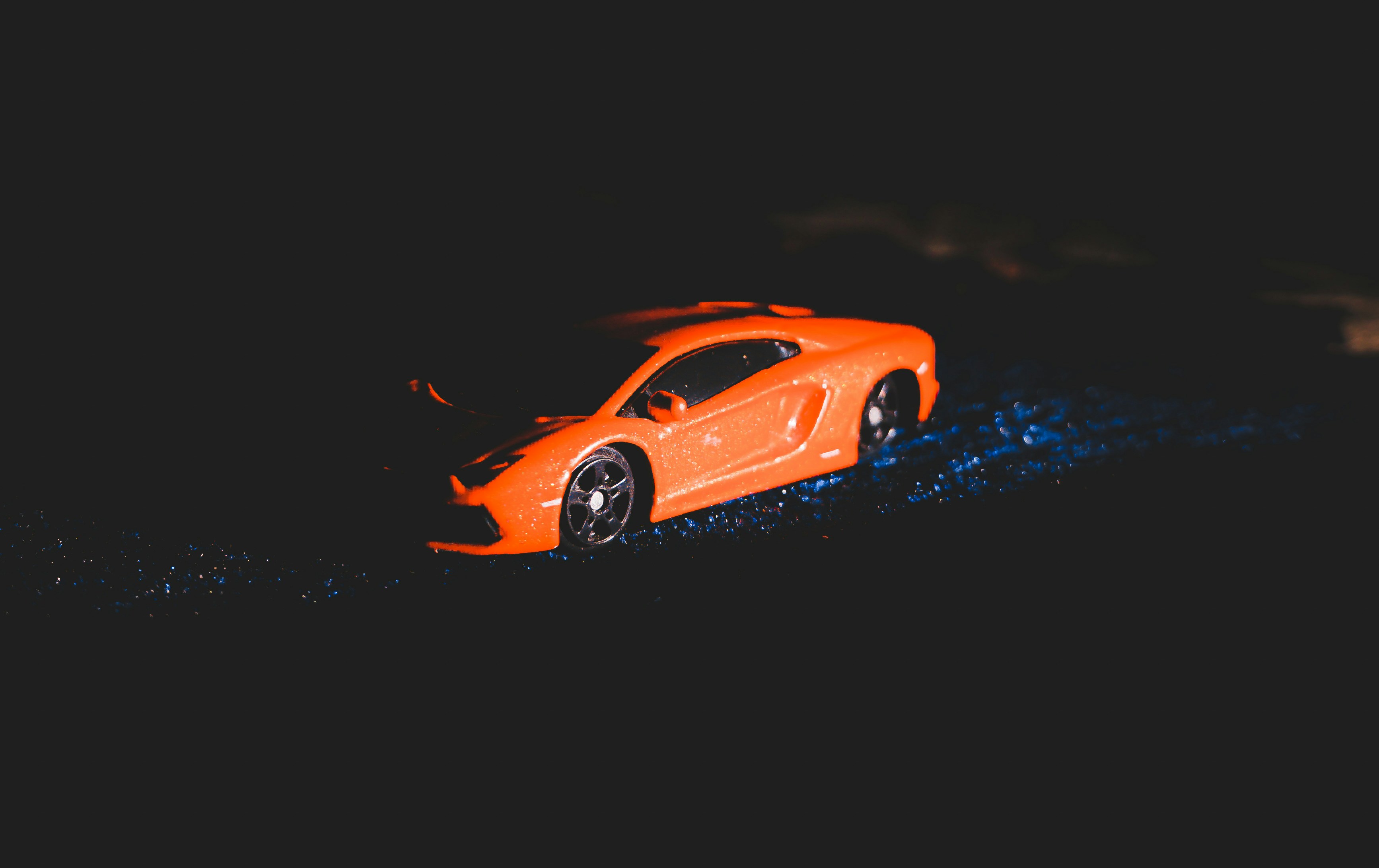 Nocturnal Blaze: Orange sports car prowling a glittering night road