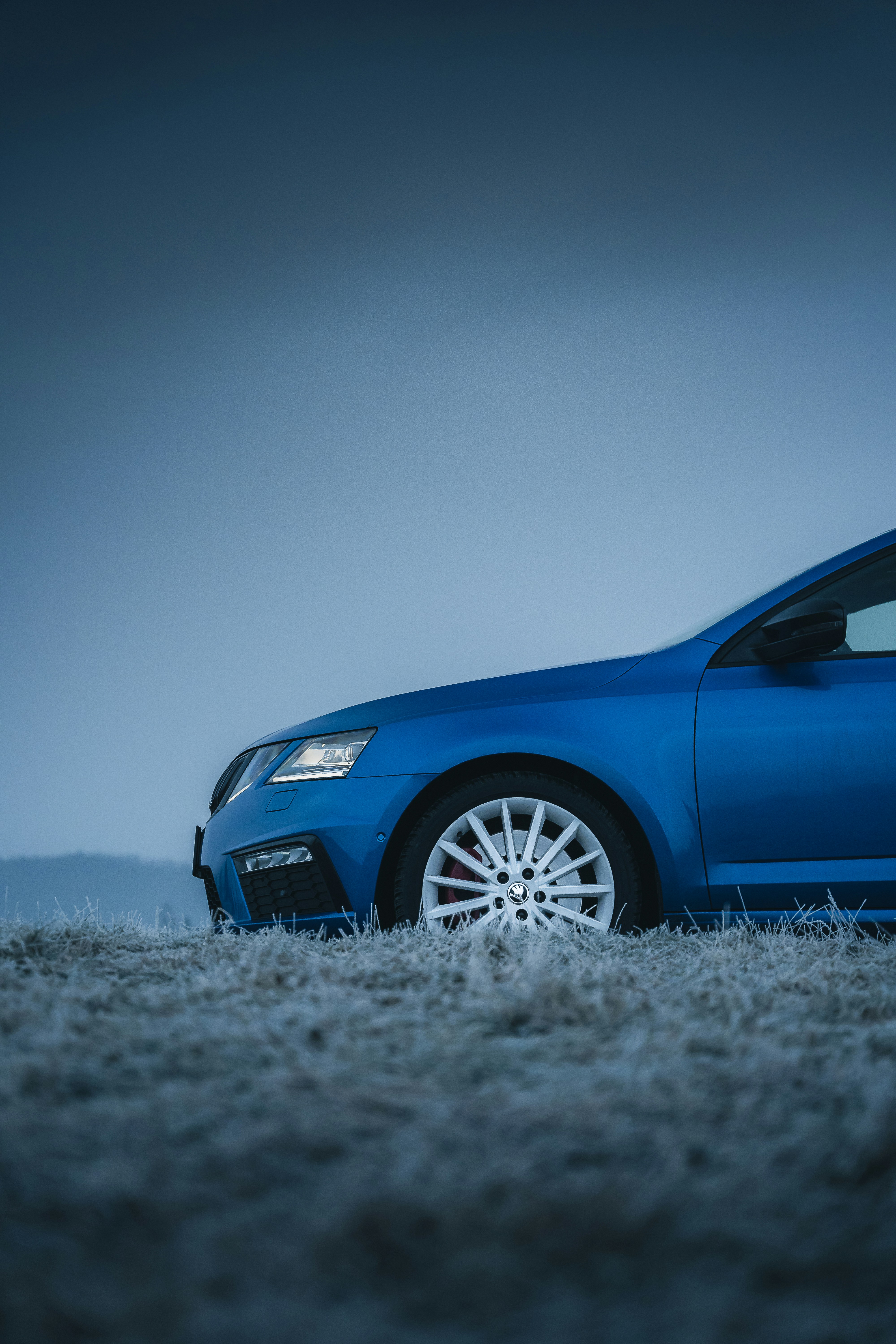 Cobalt sedan on a frost-kissed field: a low-angle study of lines and light