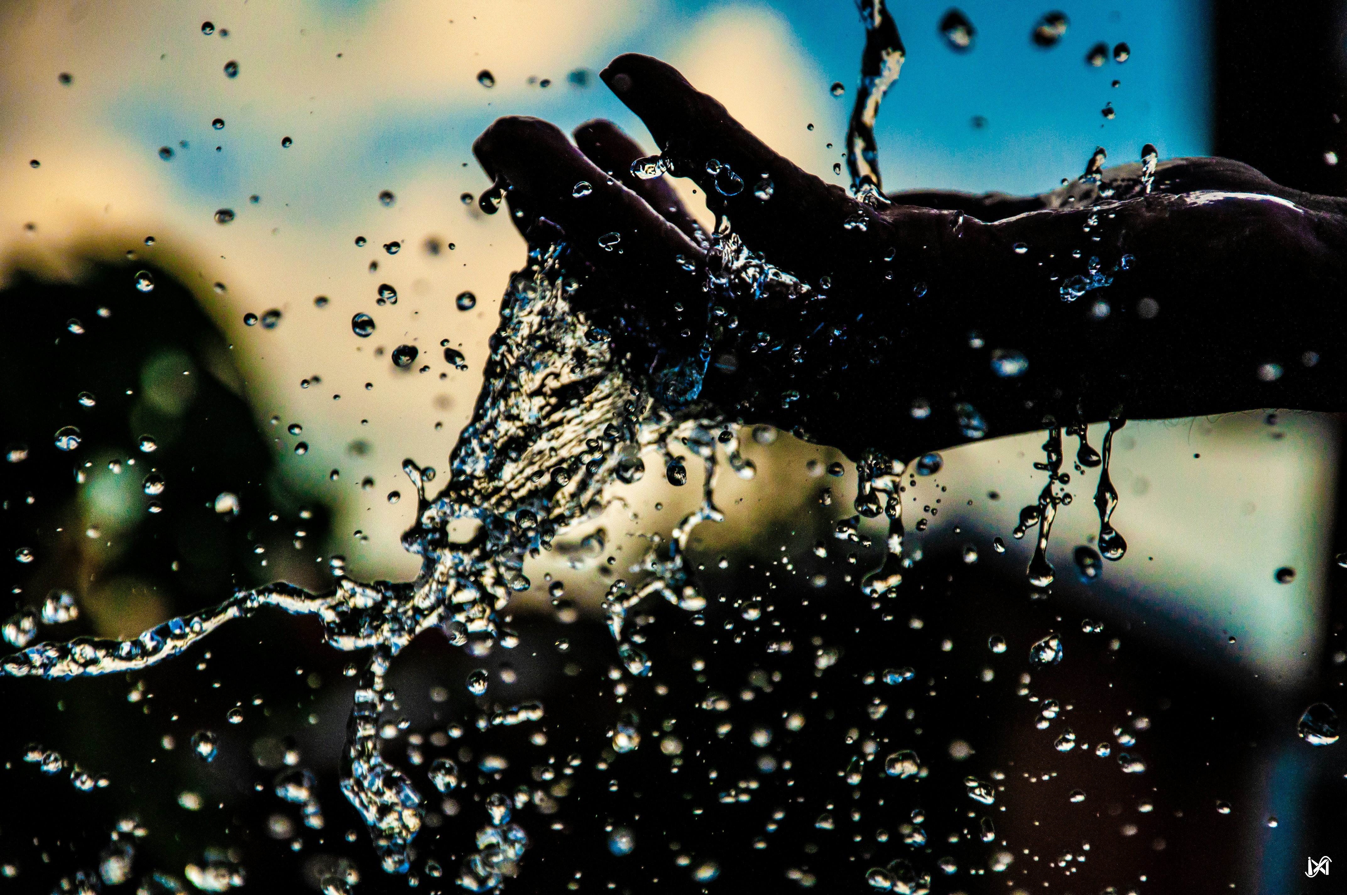 Hand splashing water droplets against a blurred background, capturing the dynamic motion and fluidity of the moment.