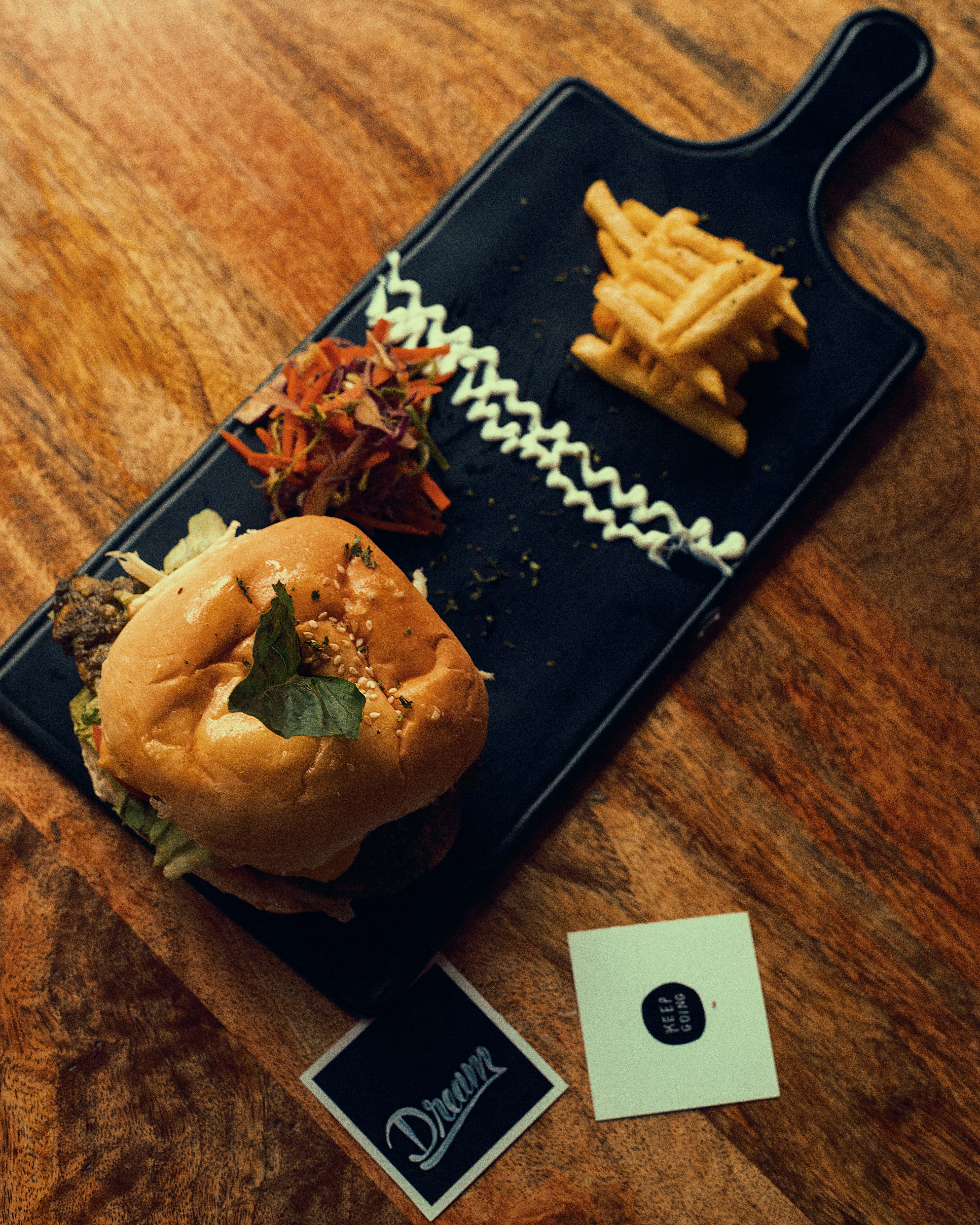 Slate-Board Burger Tableau: Greens, Fries, and a Zigzag Sauce