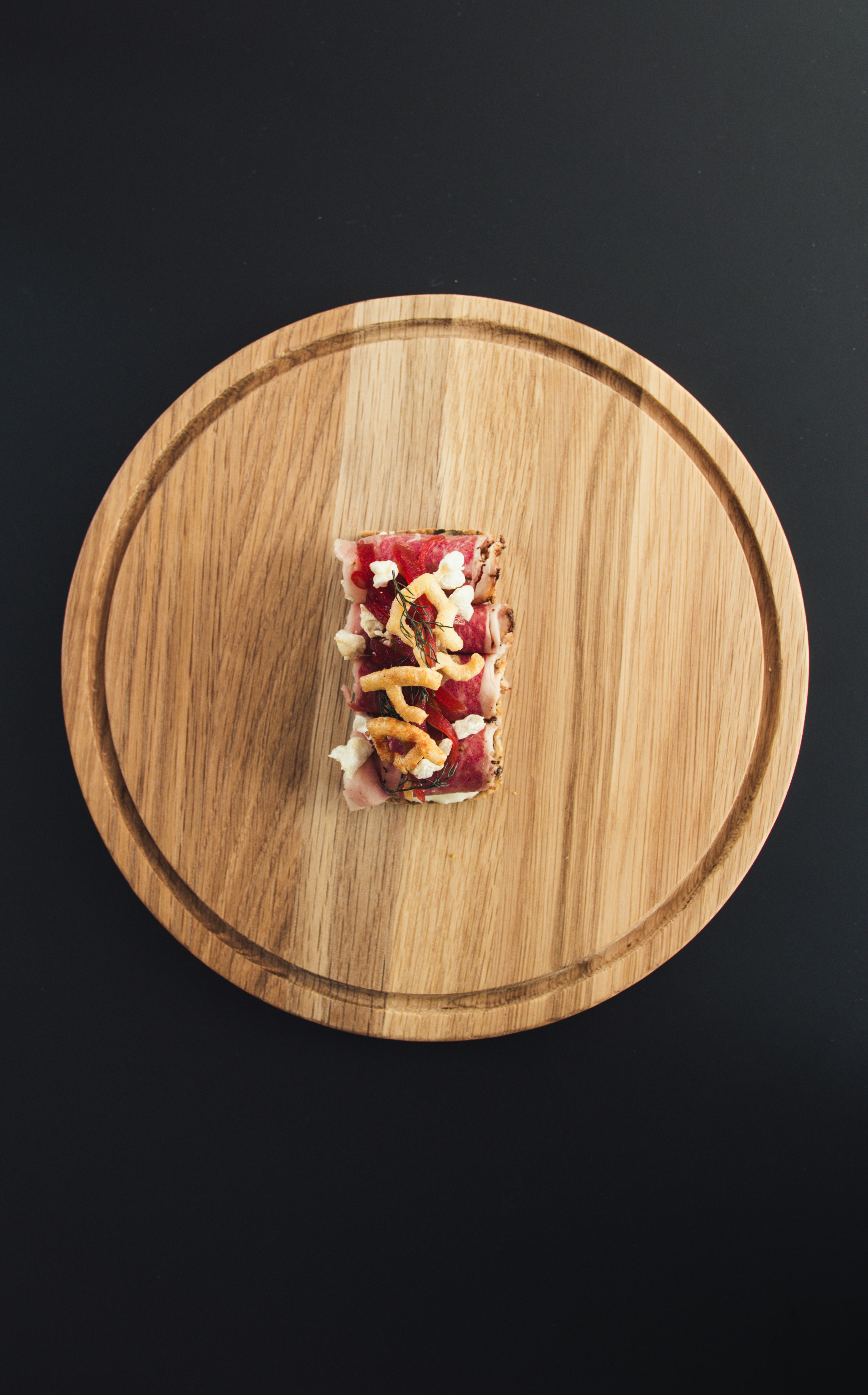 A delicately crafted sushi roll adorned with vibrant toppings, elegantly presented on a wooden serving board.