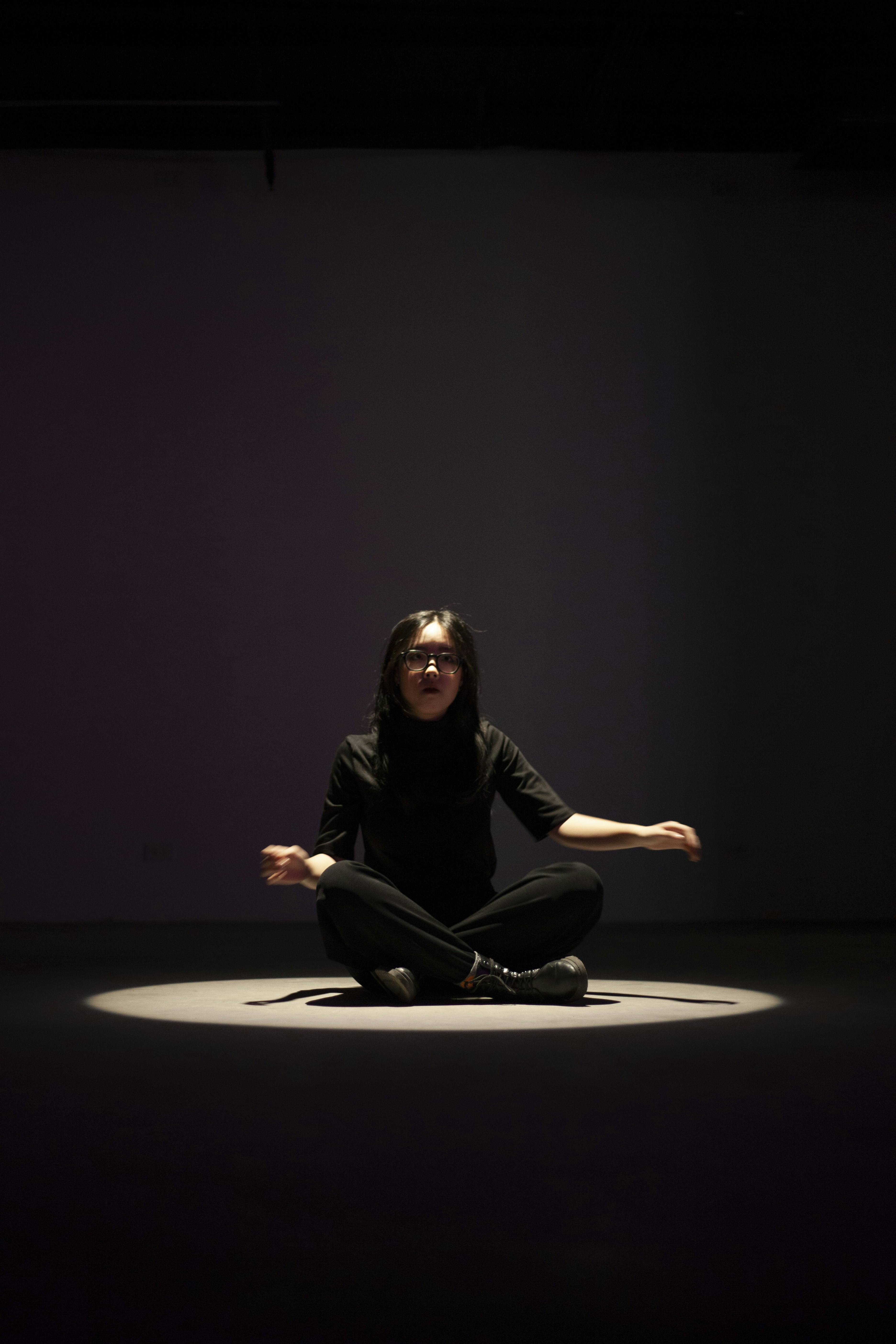 woman in black long sleeve shirt and black pants sitting on white floor
